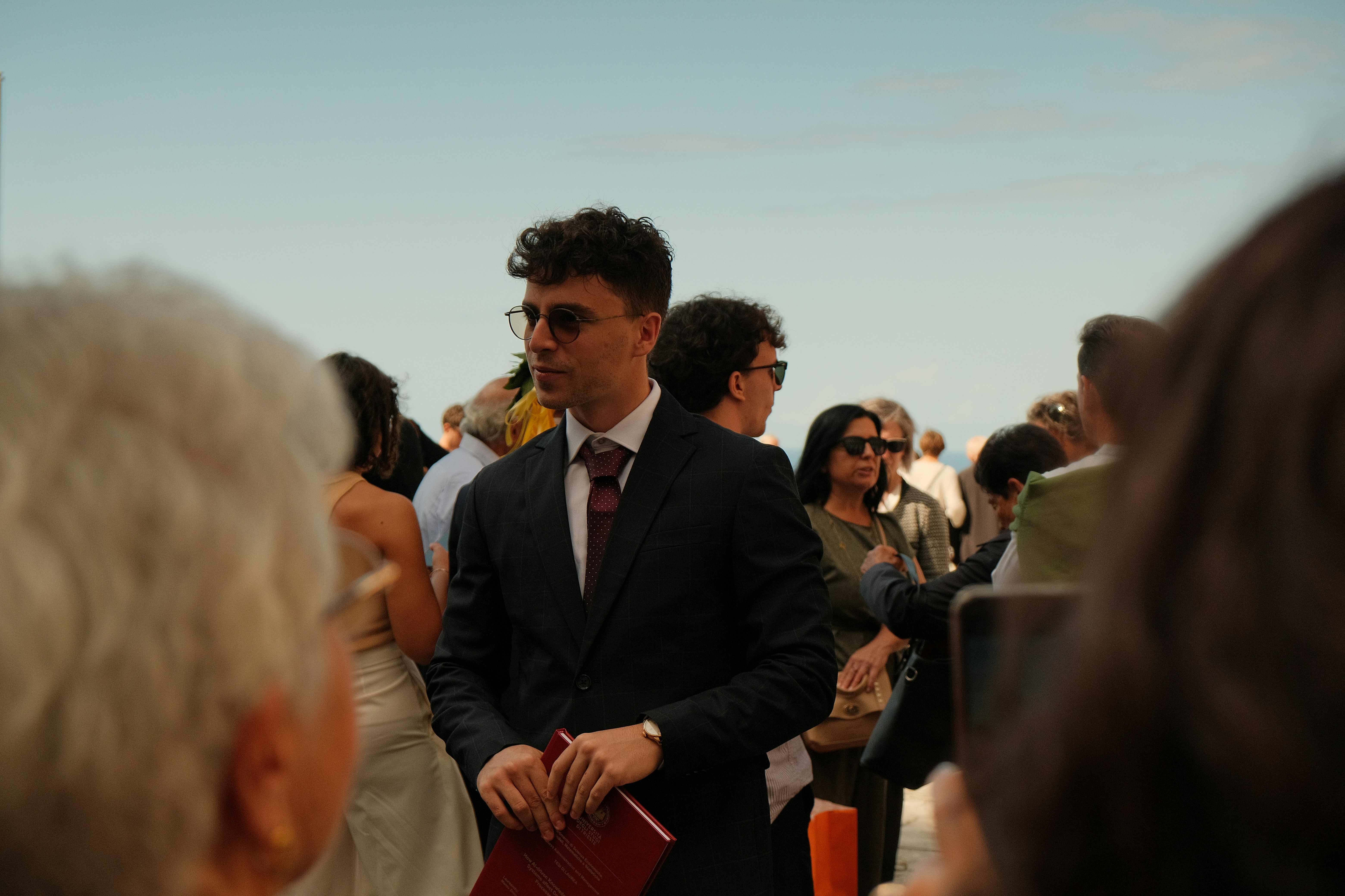 A young man in a suit walks through a crowd.