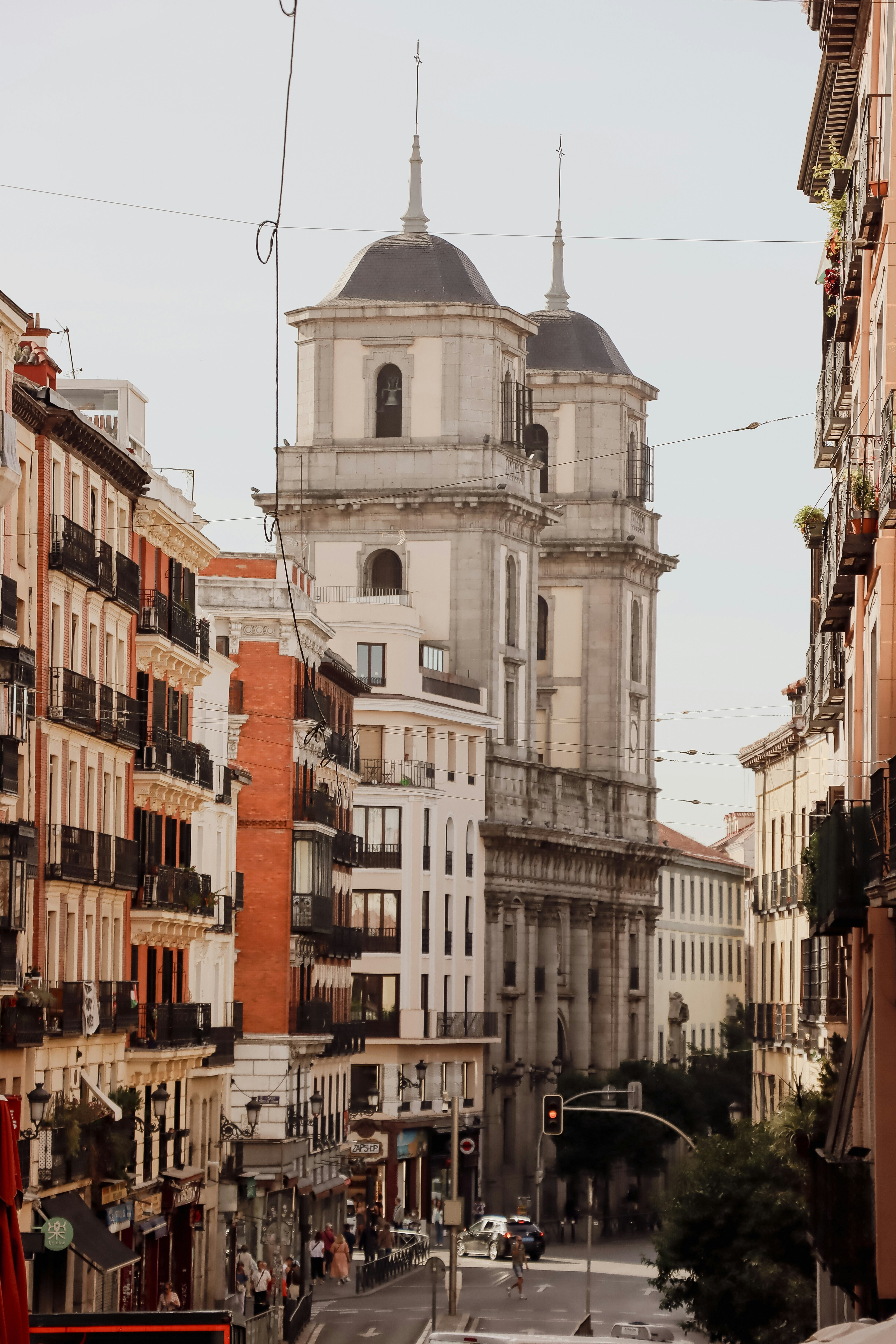 Golden hour on the streets of Madrid. | Ornate church towers overlook a european street scene.