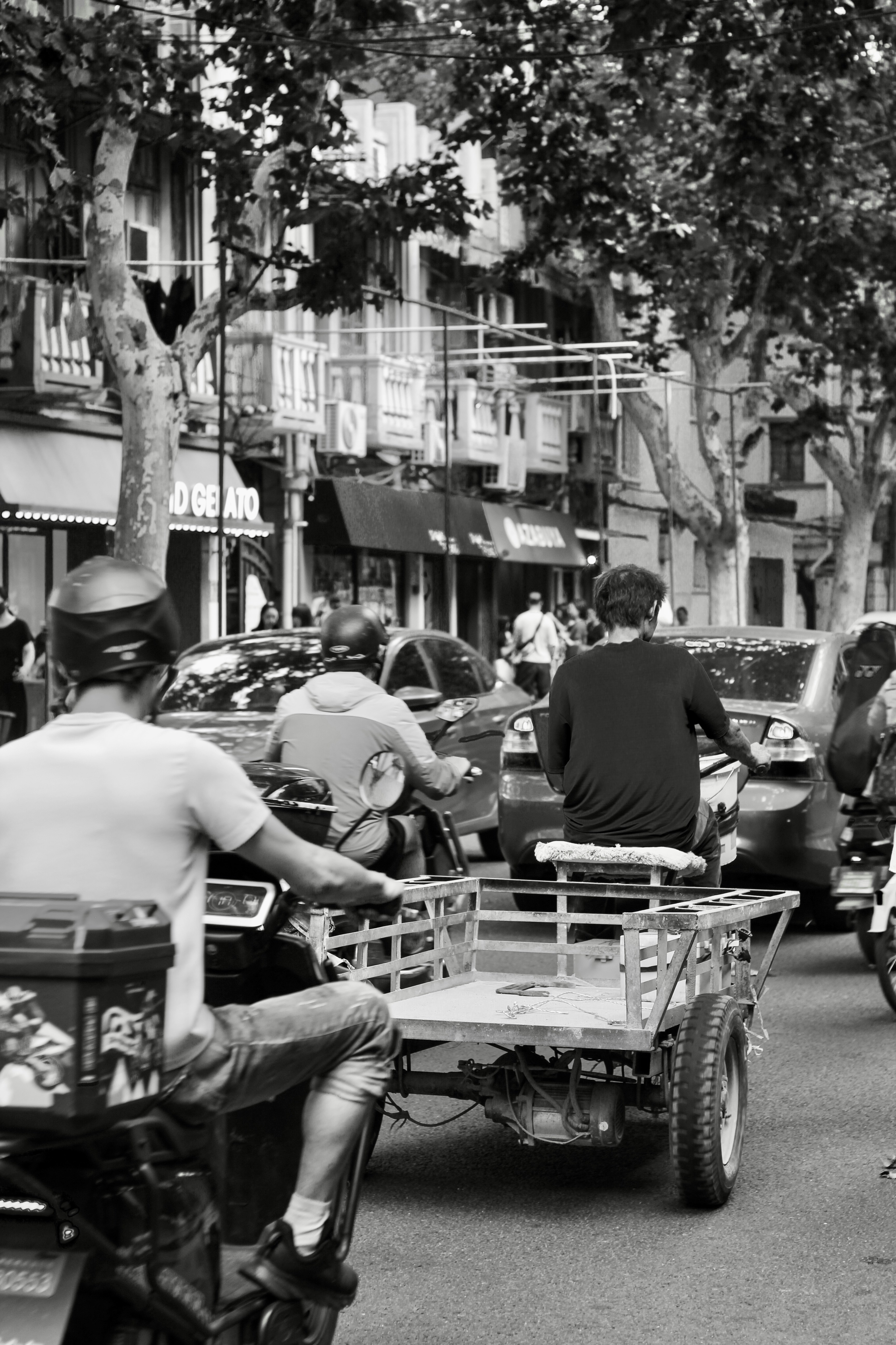 People riding motorcycles with trailers on a street.