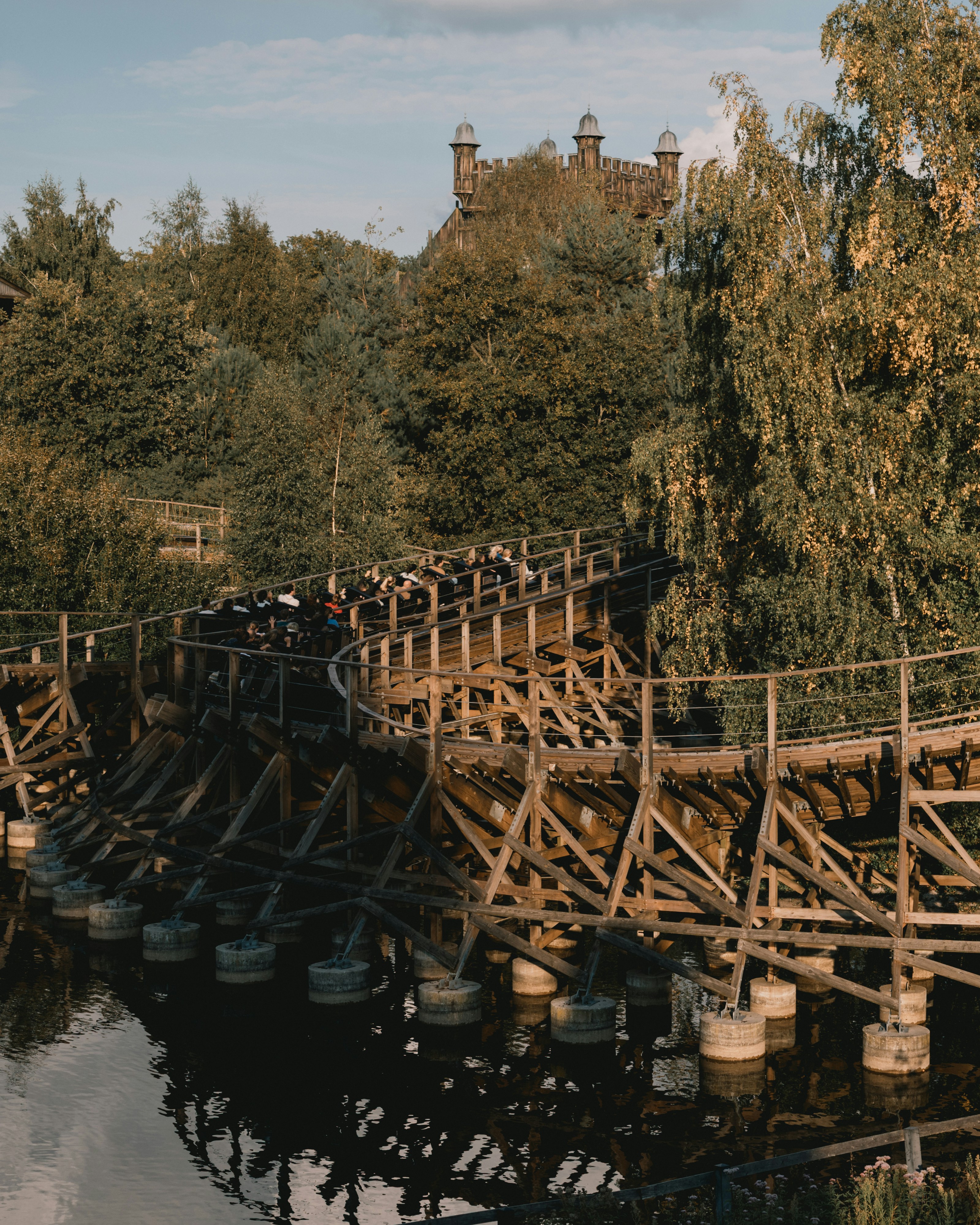 Wooden roller coaster over water with castle
