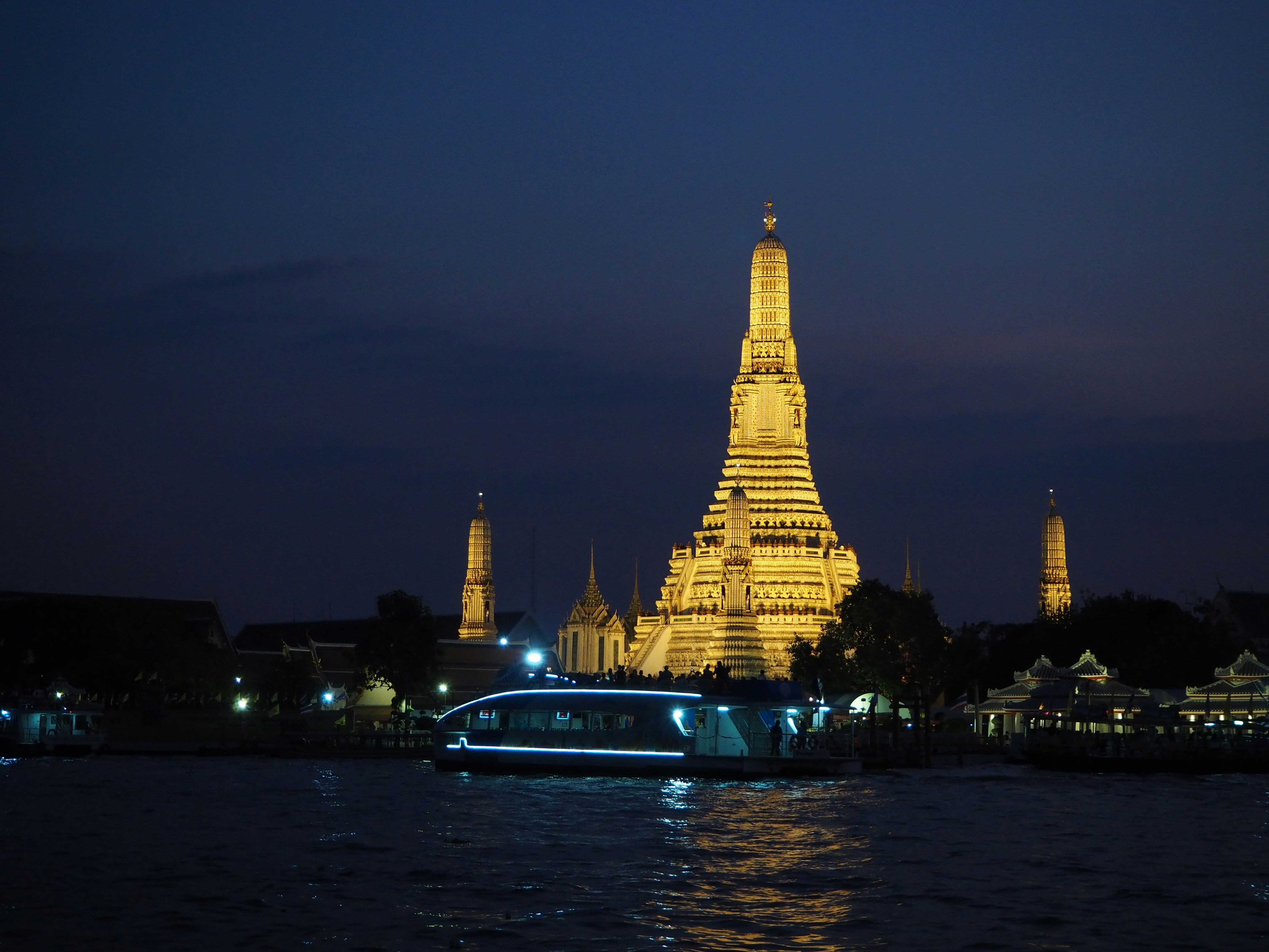WAT ARUN THE TEMPLE OF DAWN in Night View | Temple illuminated at night with a boat on the river.