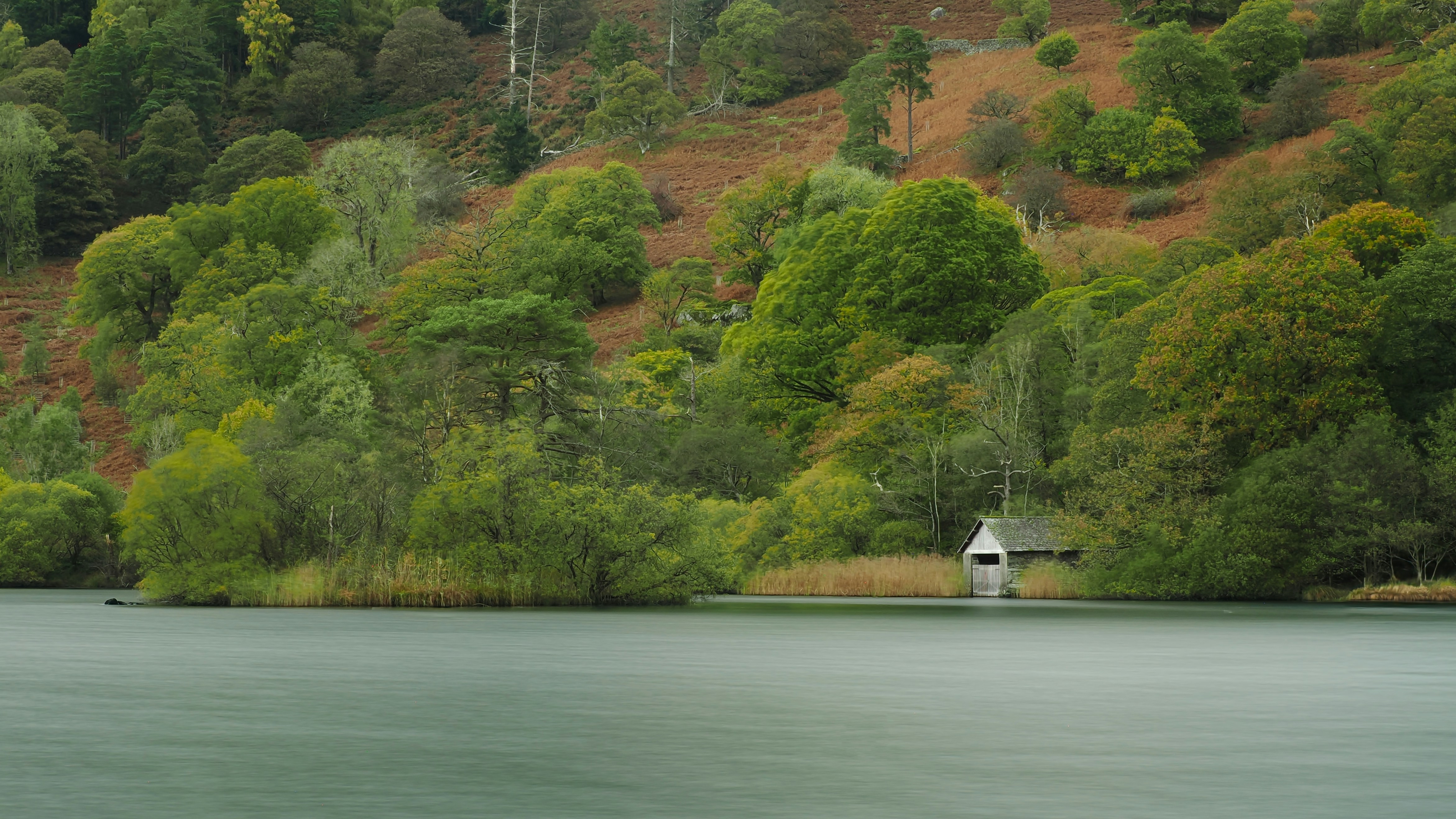 A boathouse nestled among lush green trees by a lake.