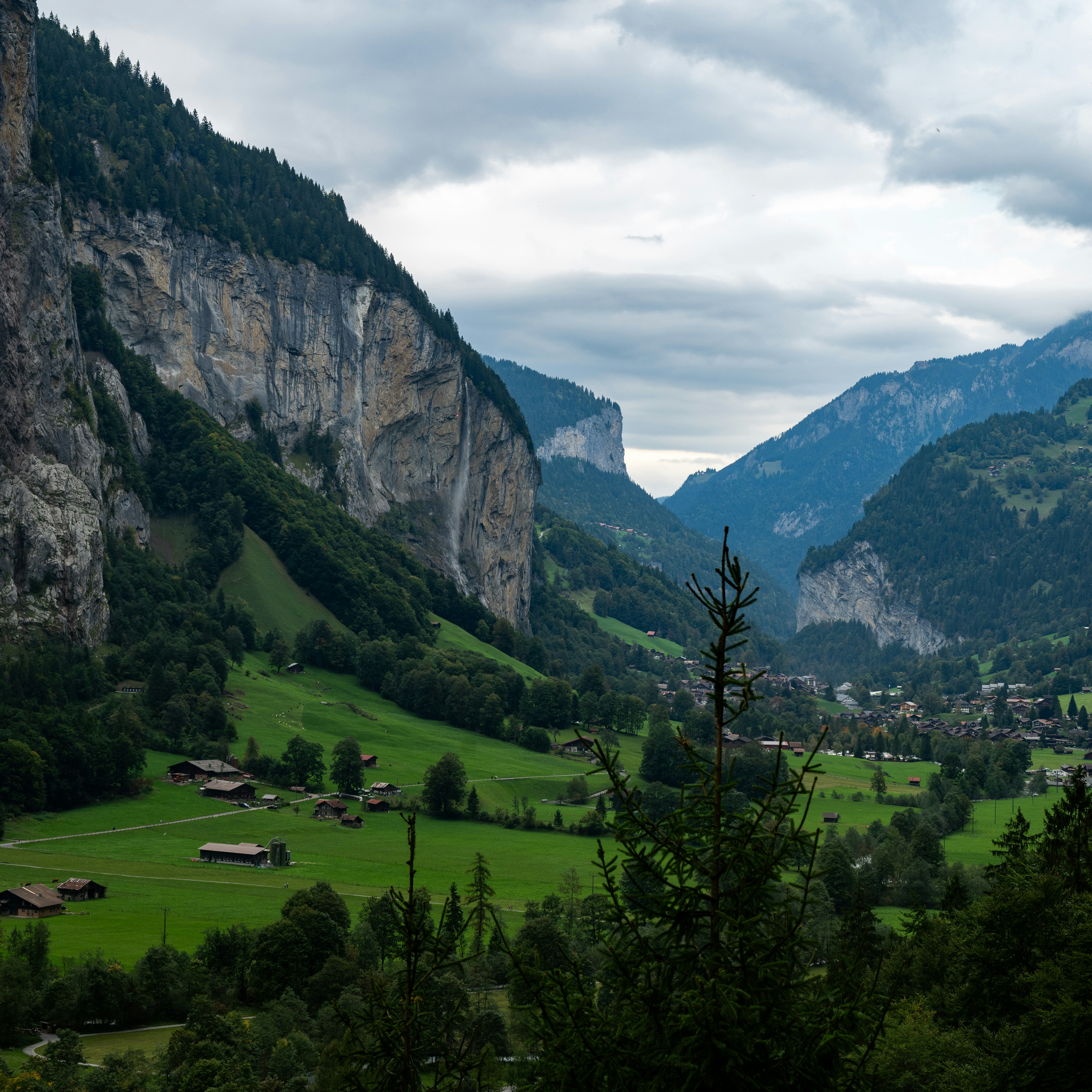 Dramatic cliffs overlook a green valley with a village.