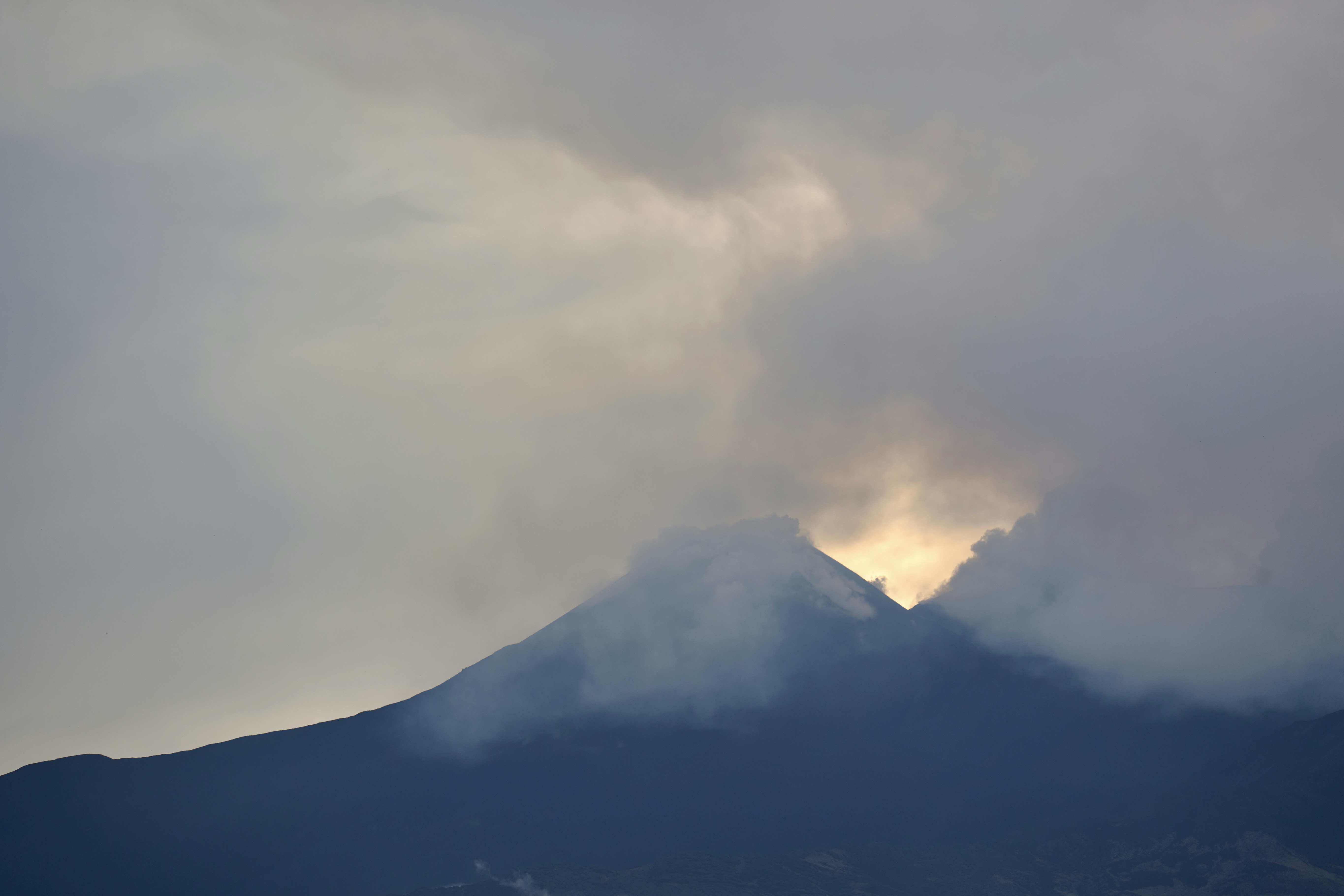 Sunlight peeking through clouds over mountain peaks.
