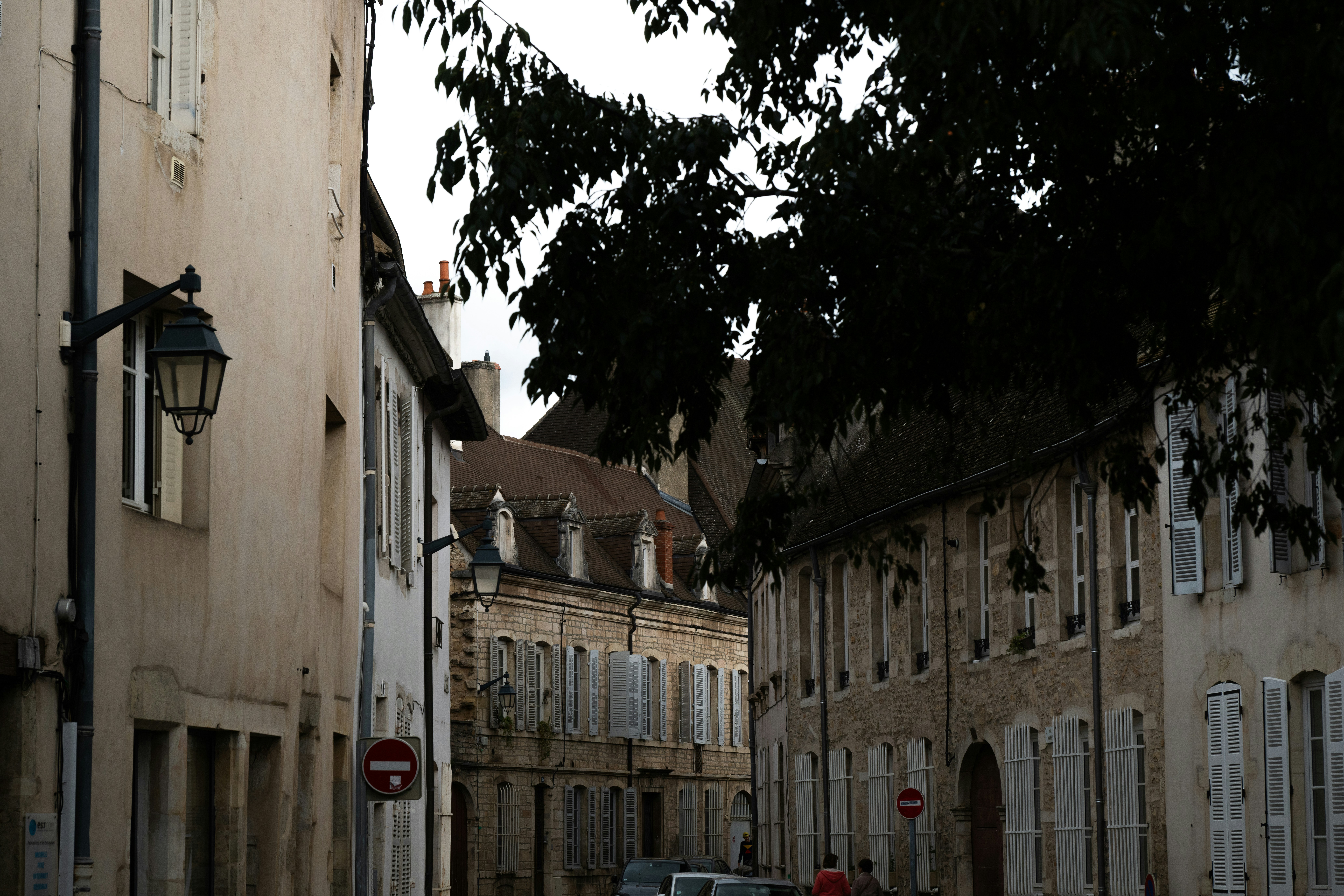 Charming narrow street lined with historic buildings and lush foliage, inviting exploration. A soft glow from a lantern adds warmth to the scene.