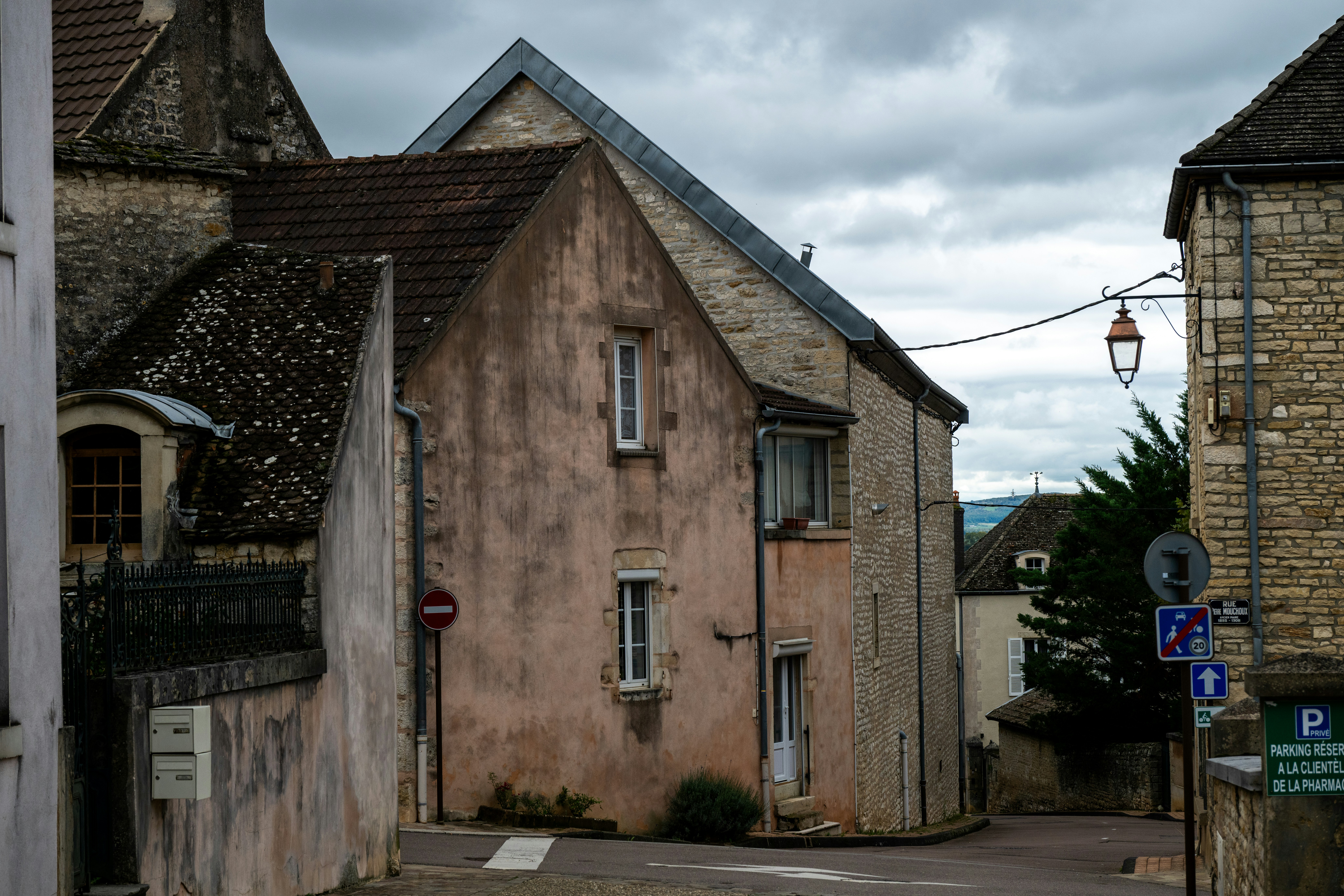 Charming rustic buildings line a quiet street, showcasing weathered textures and soft hues under an overcast sky.