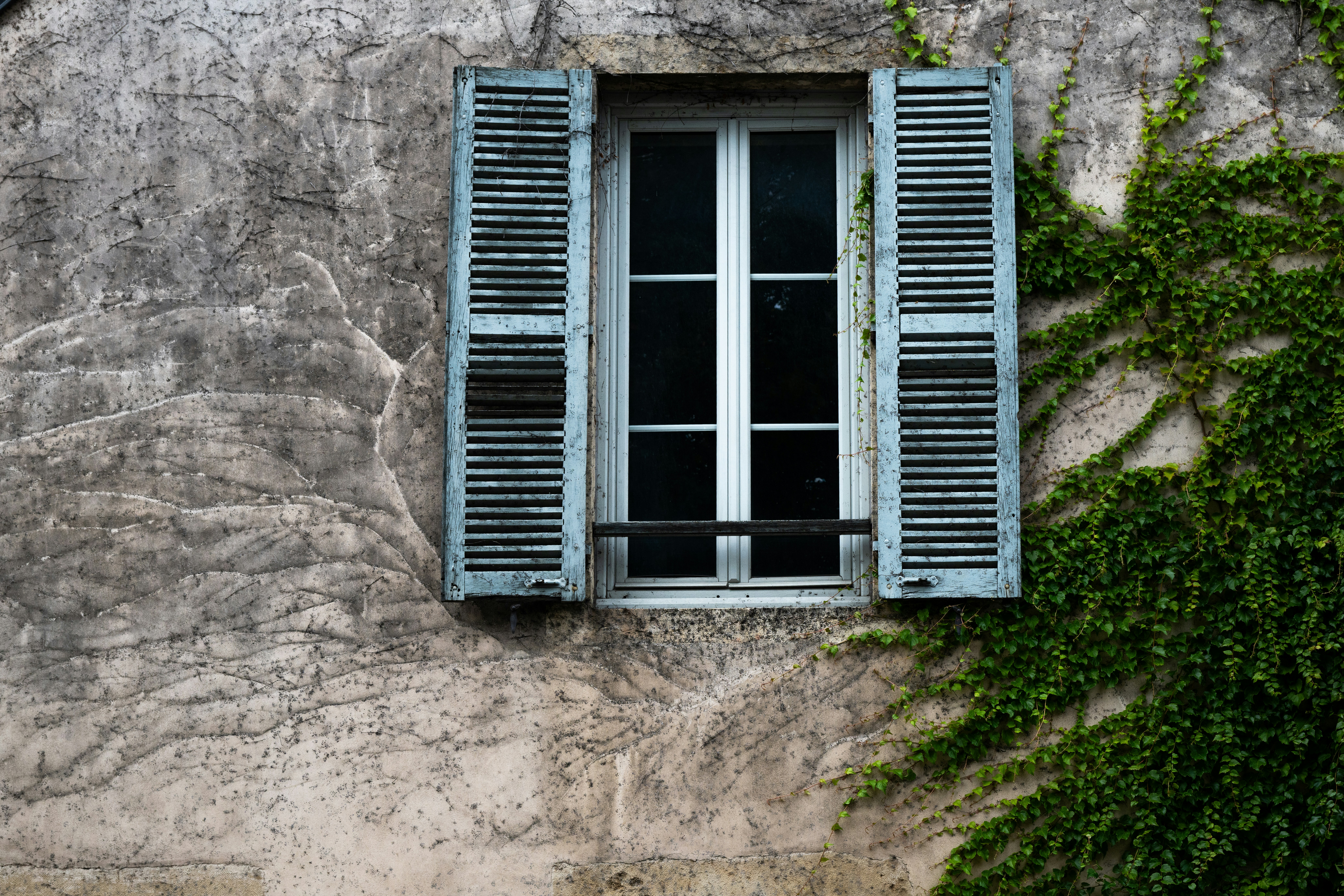 Window with open shutters on a textured wall