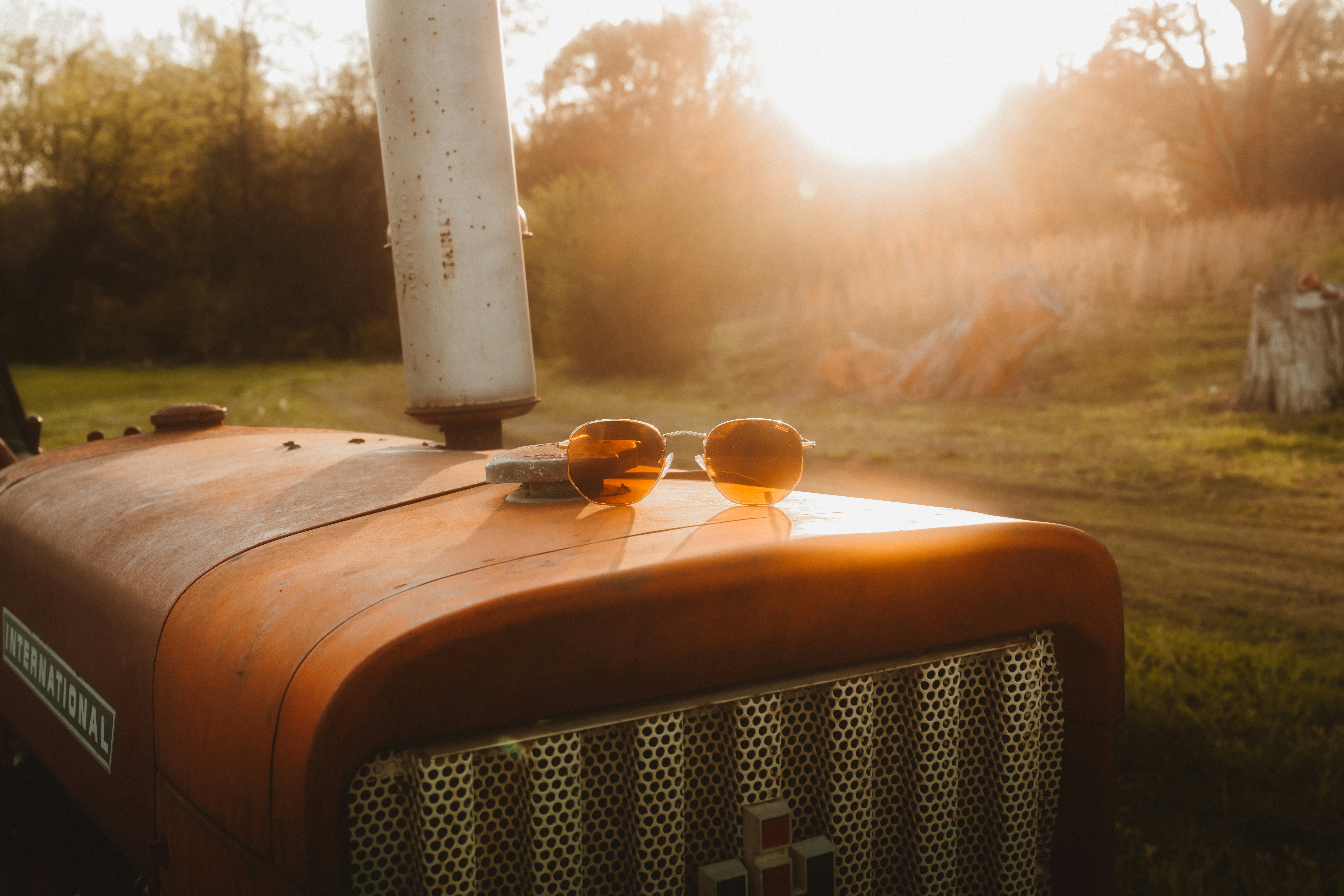 Old orange tractor in field at sunset