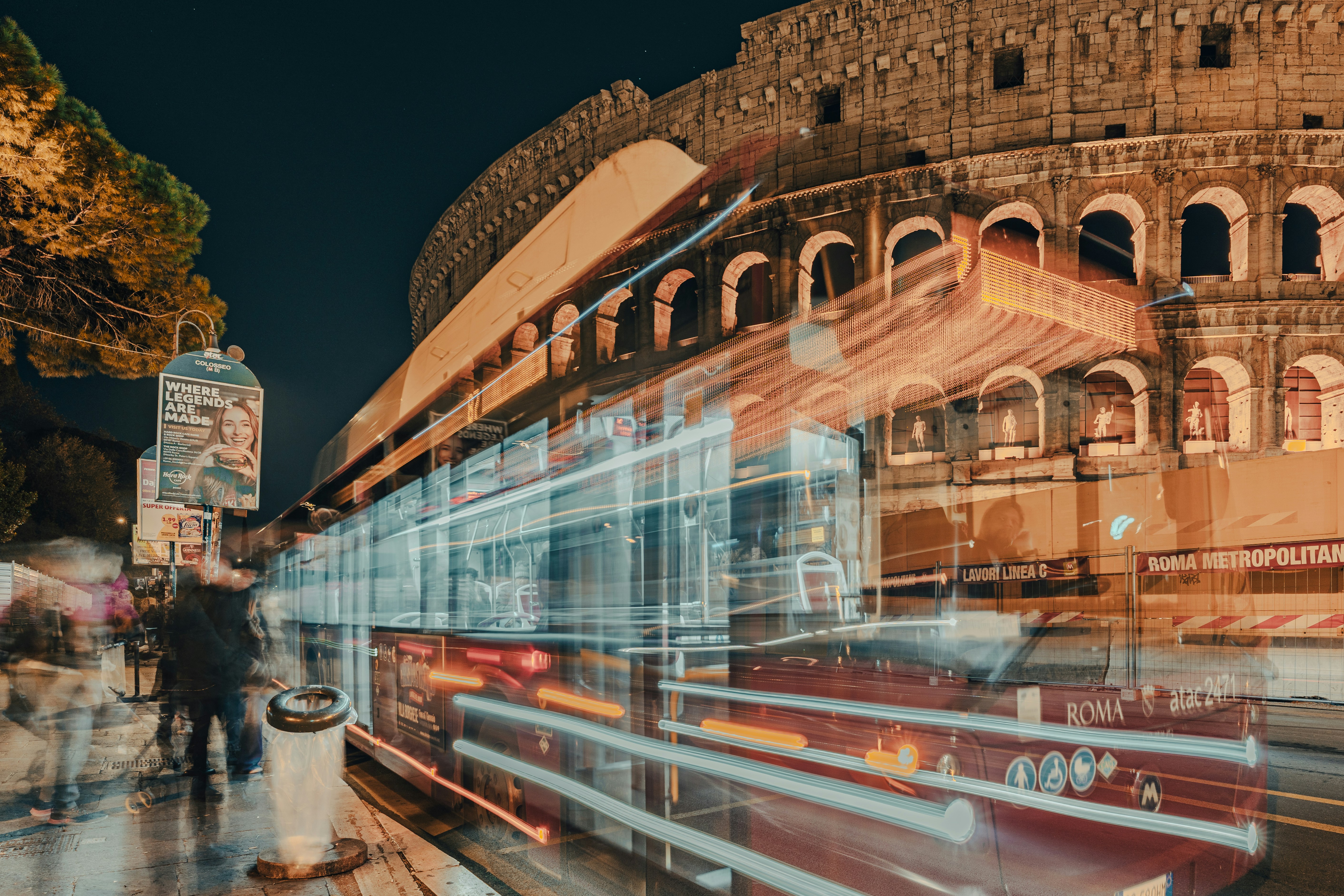 An evening stop at the Colosseo in Rome as a bus passes by, shot with a long exposure | Double-decker bus passes colosseum at night
