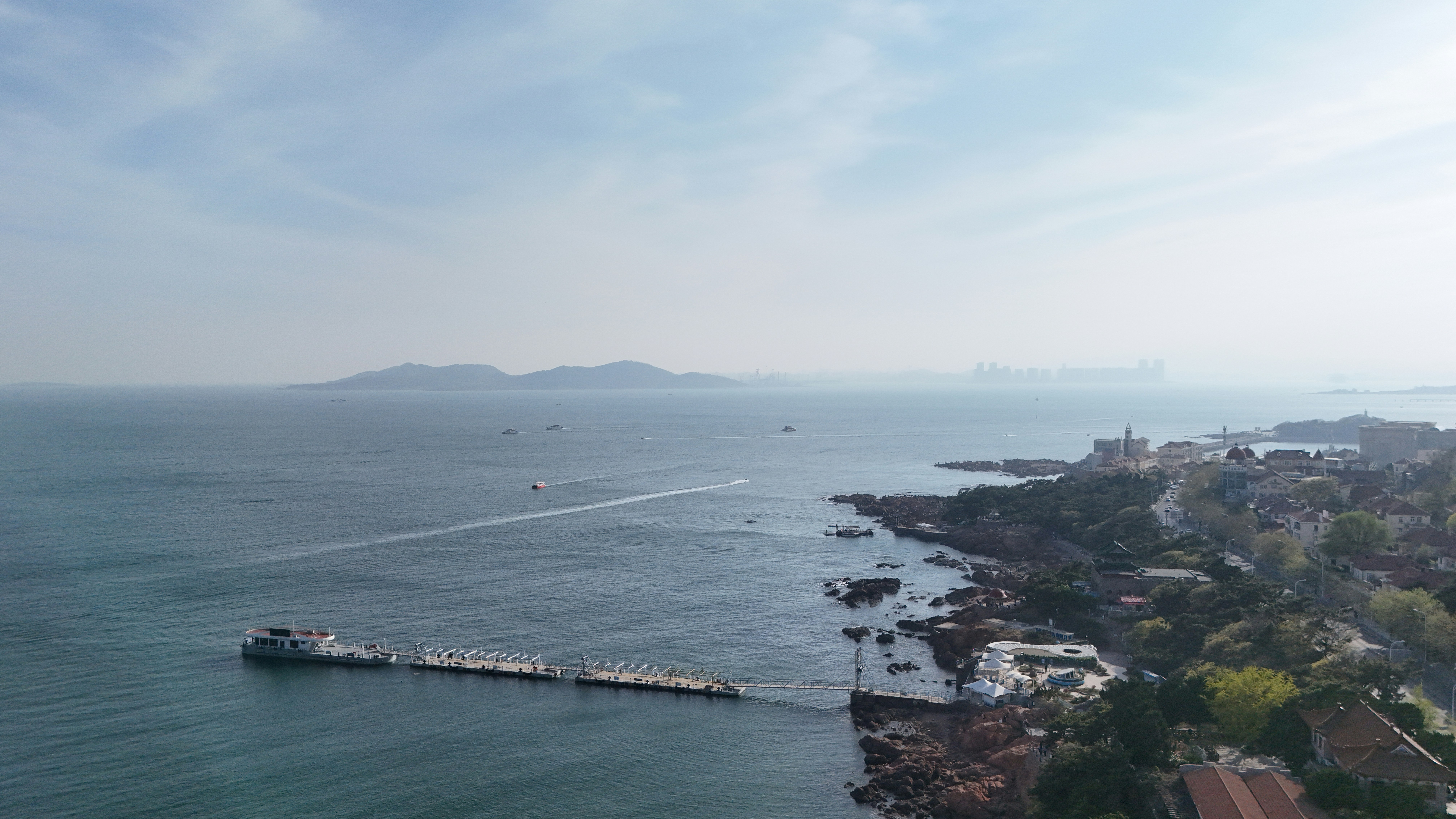 Ships docked along a coastal city with distant islands.