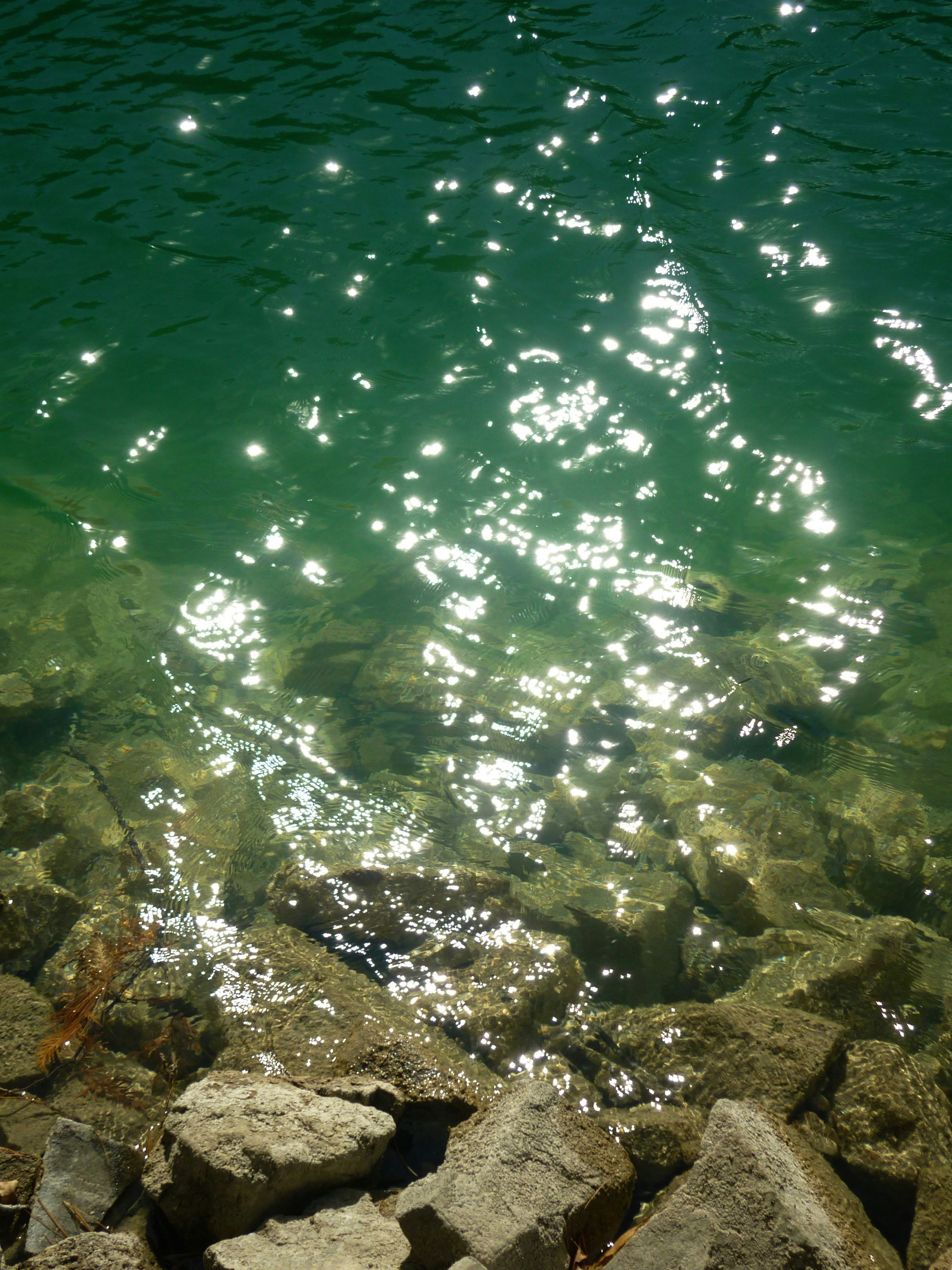 Sparkling sunlight on clear water over rocks.