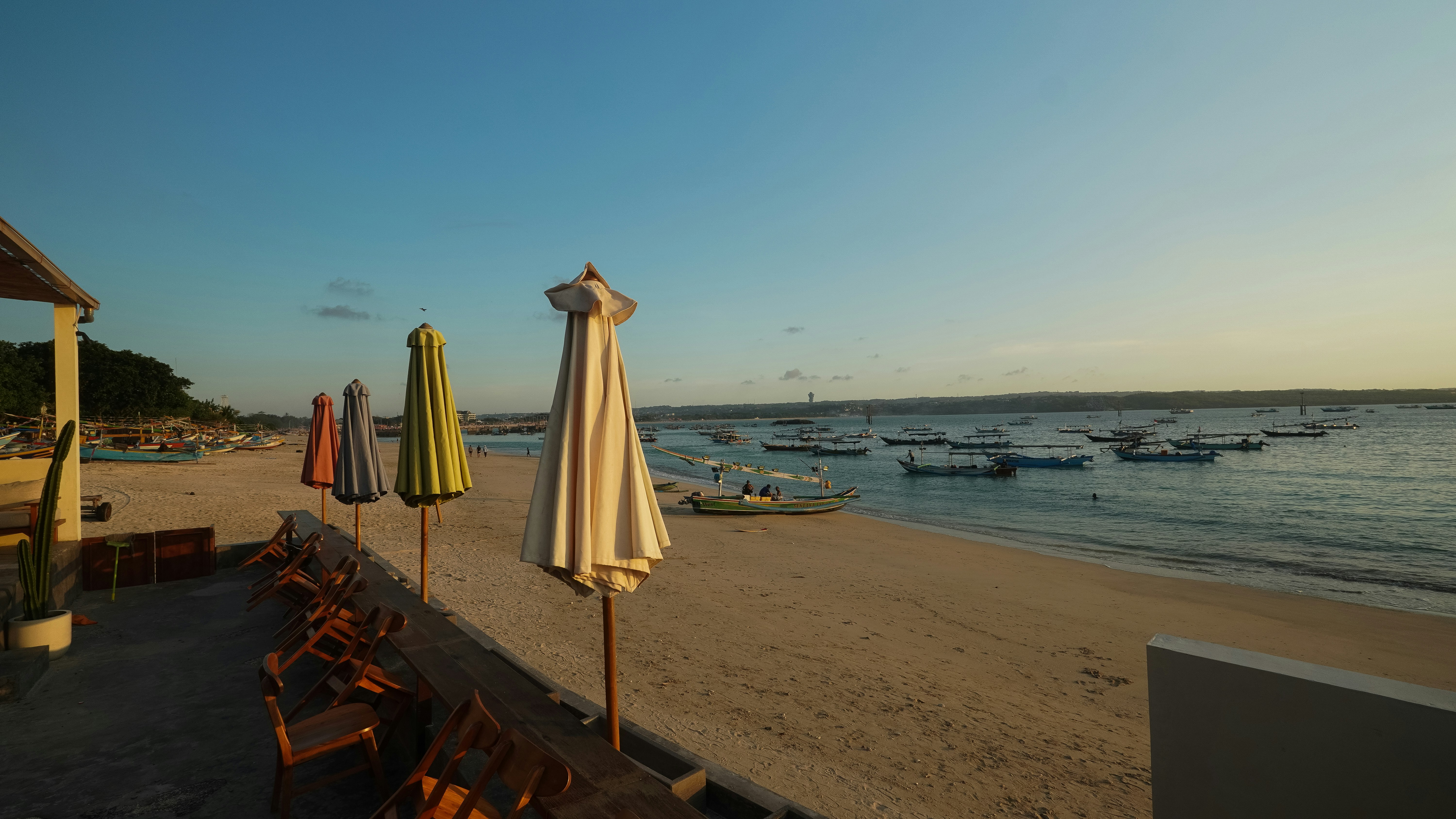 Beach umbrellas and chairs overlook calm ocean waters.