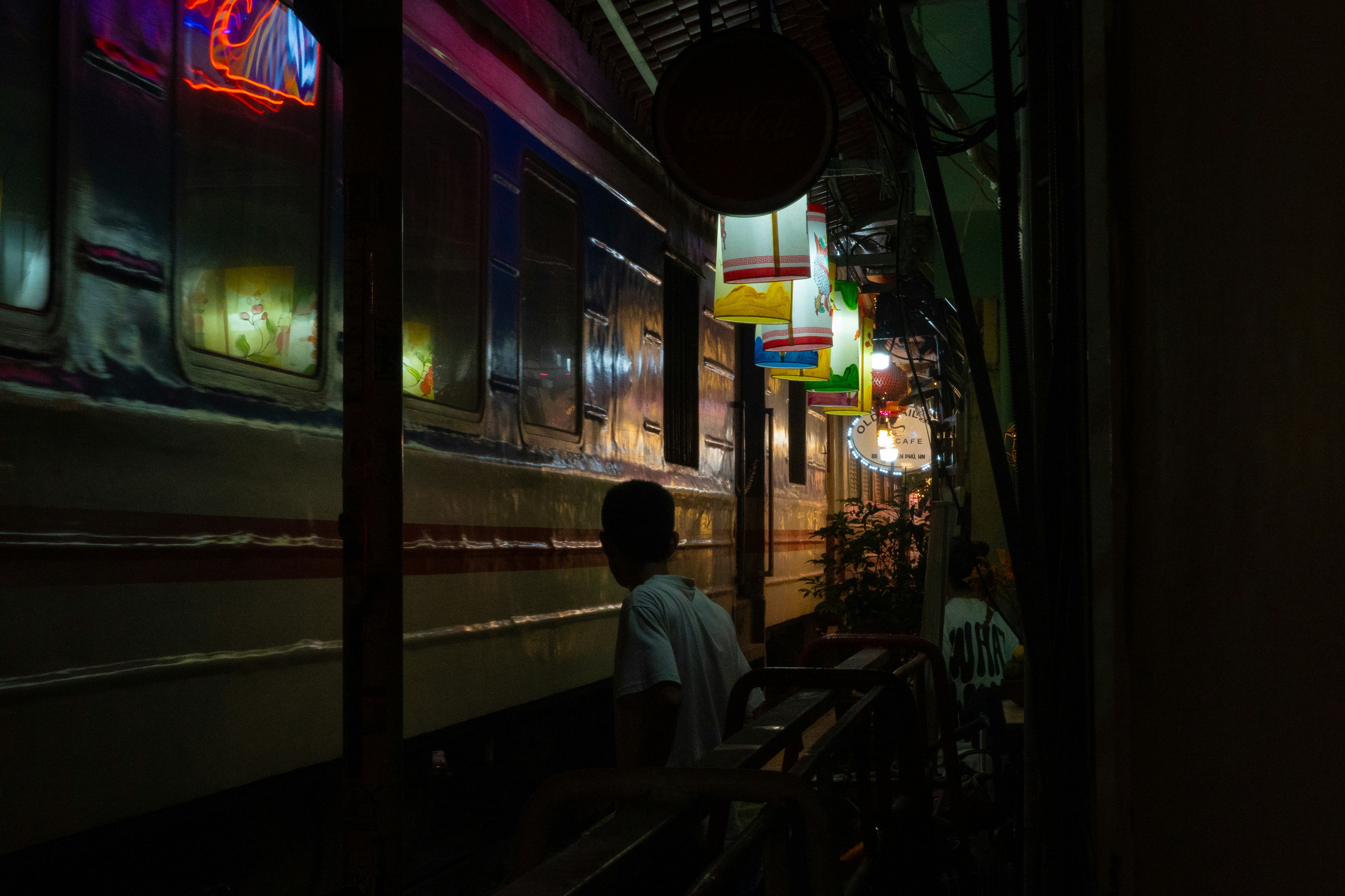 People walk past a train at night.