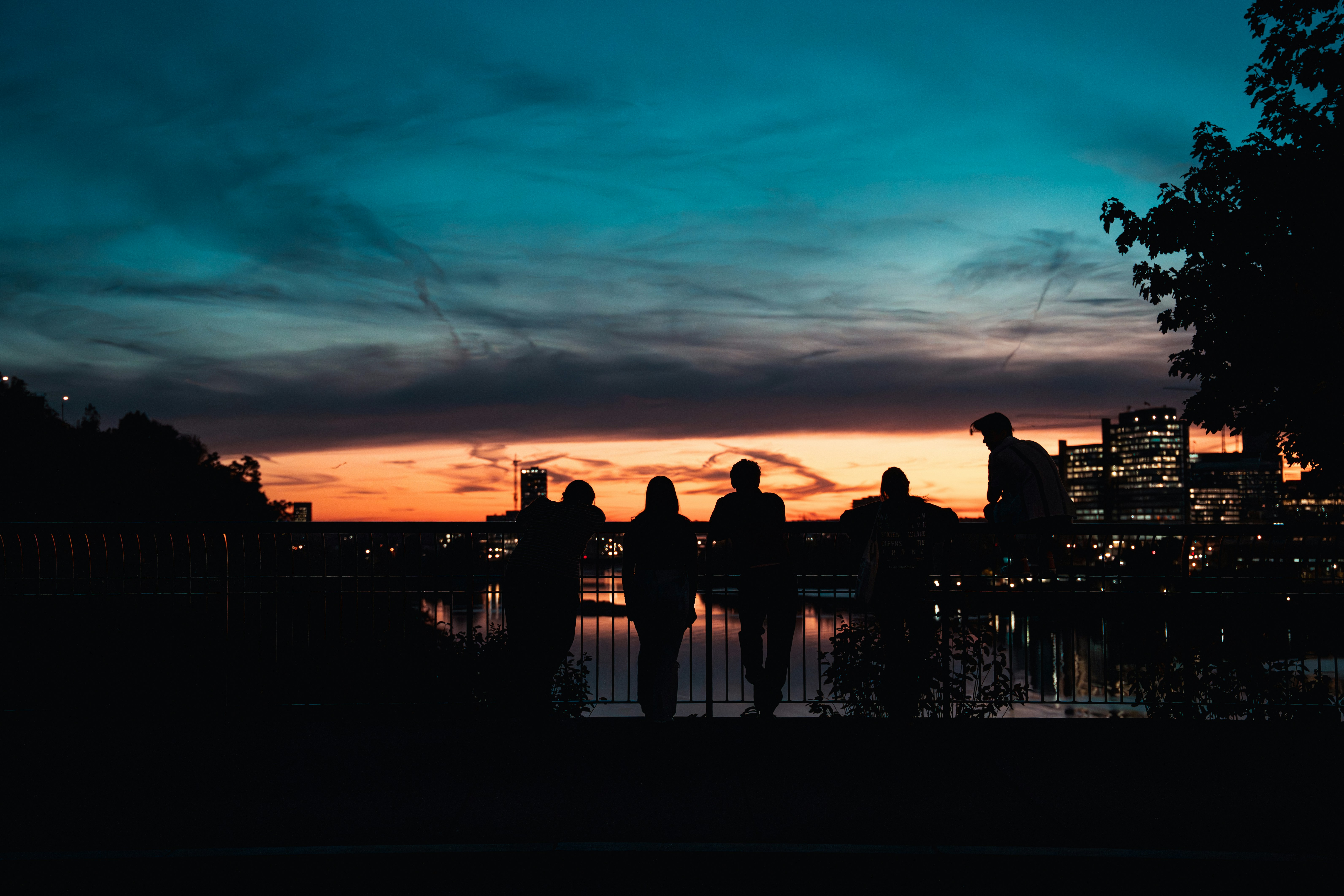 Silhouettes of people watching a vibrant sunset over a city.