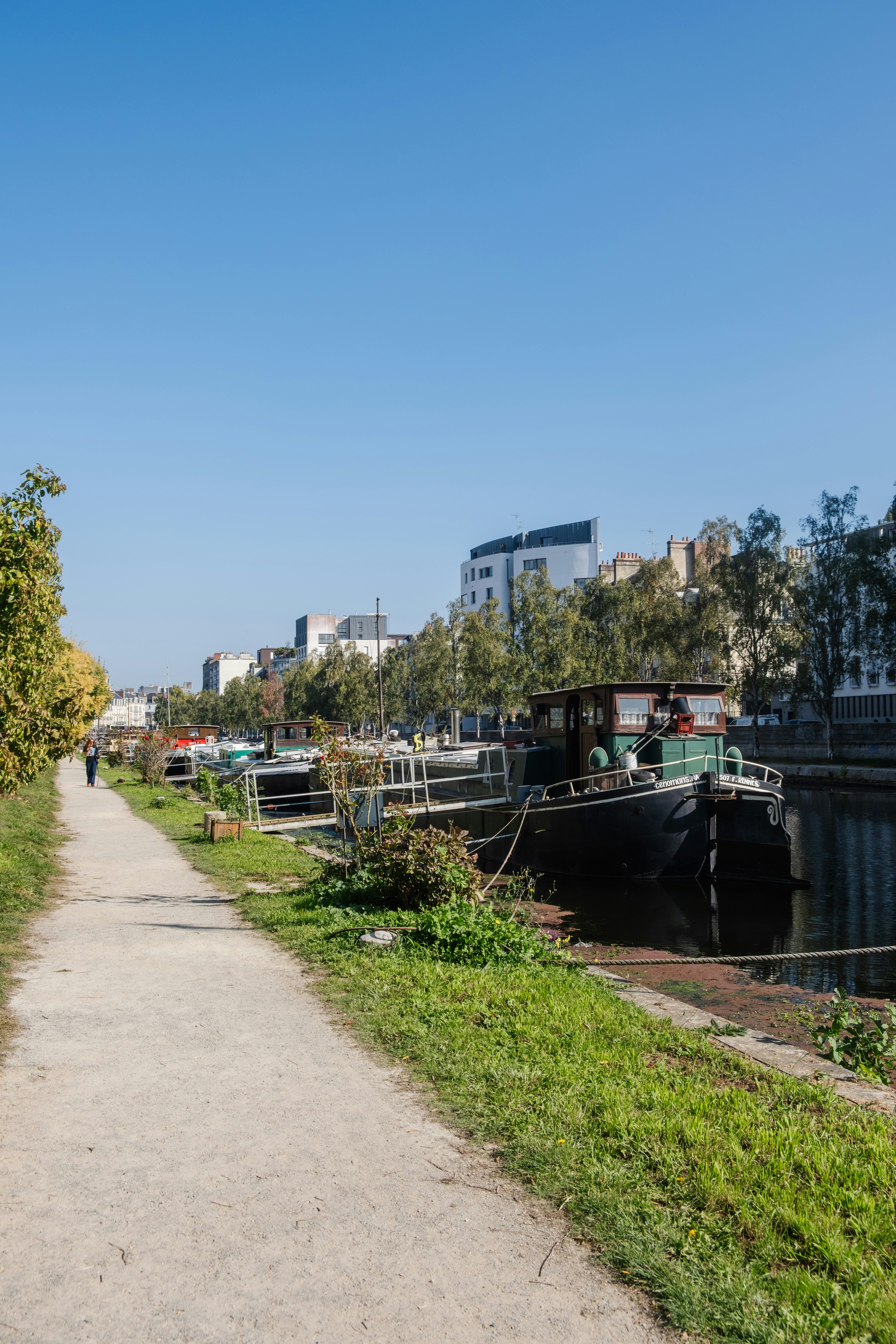 A canal path with boats docked alongside buildings.