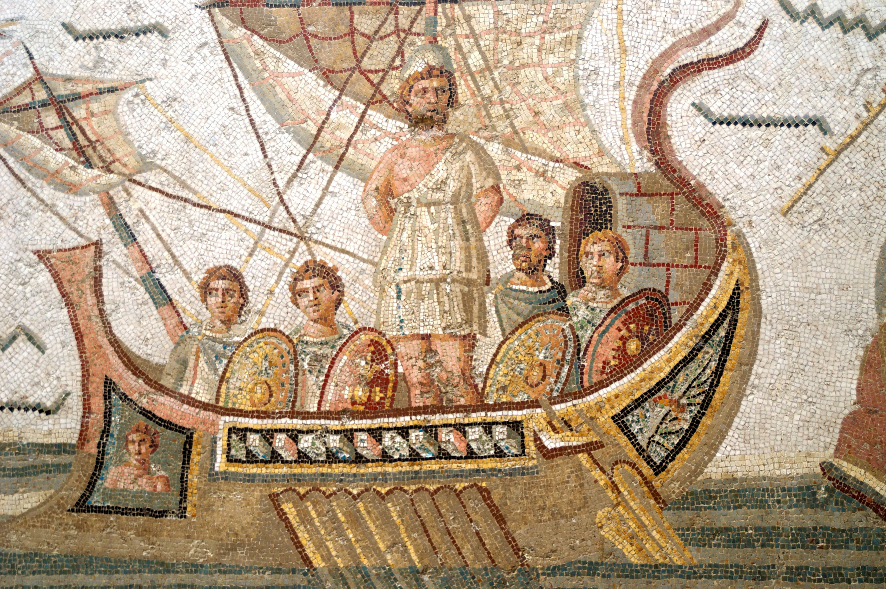 Ancient mosaic of men on a ship with sails.