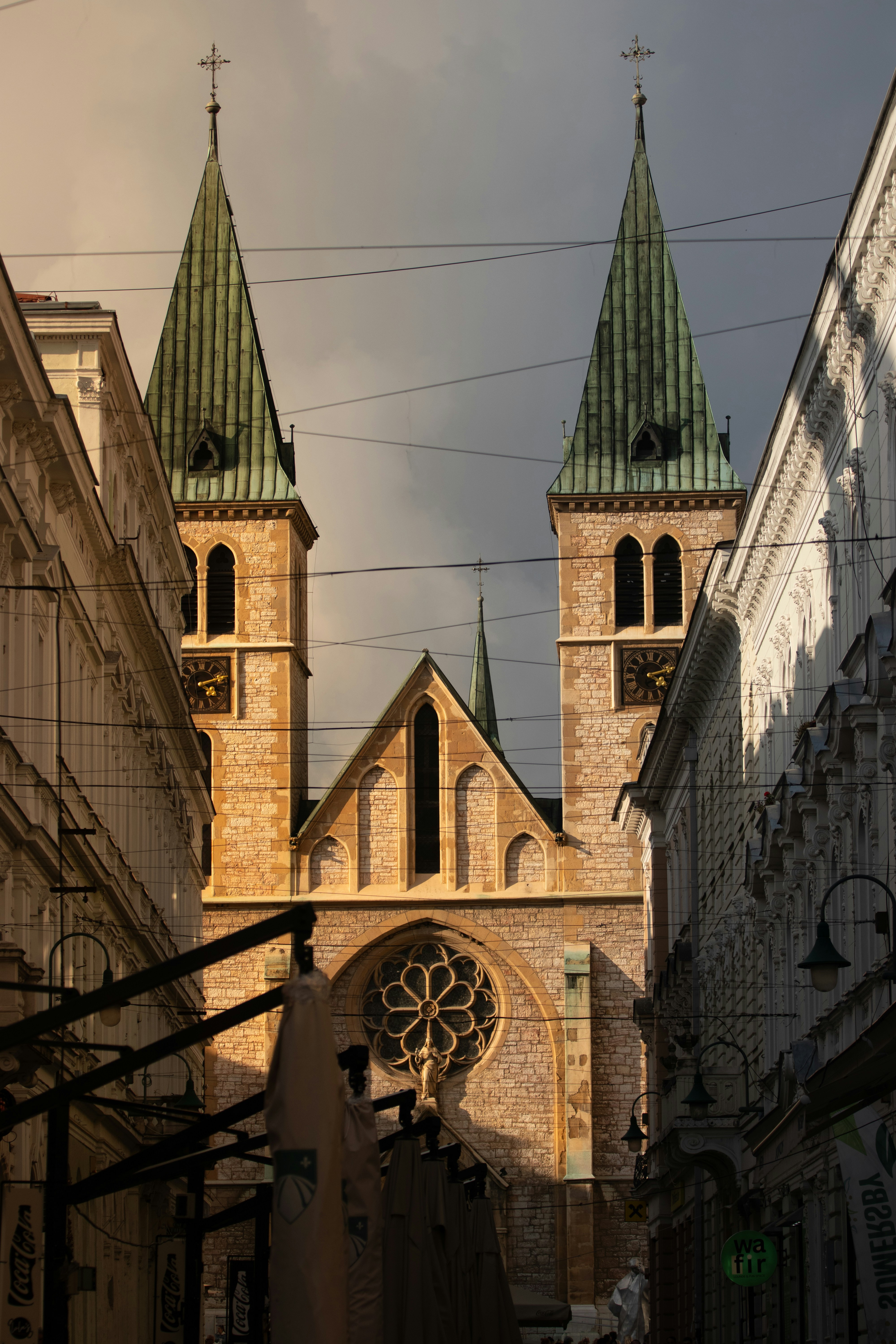 Sarajevo, Bosnia and Herzegovina | Two church towers with green roofs between buildings