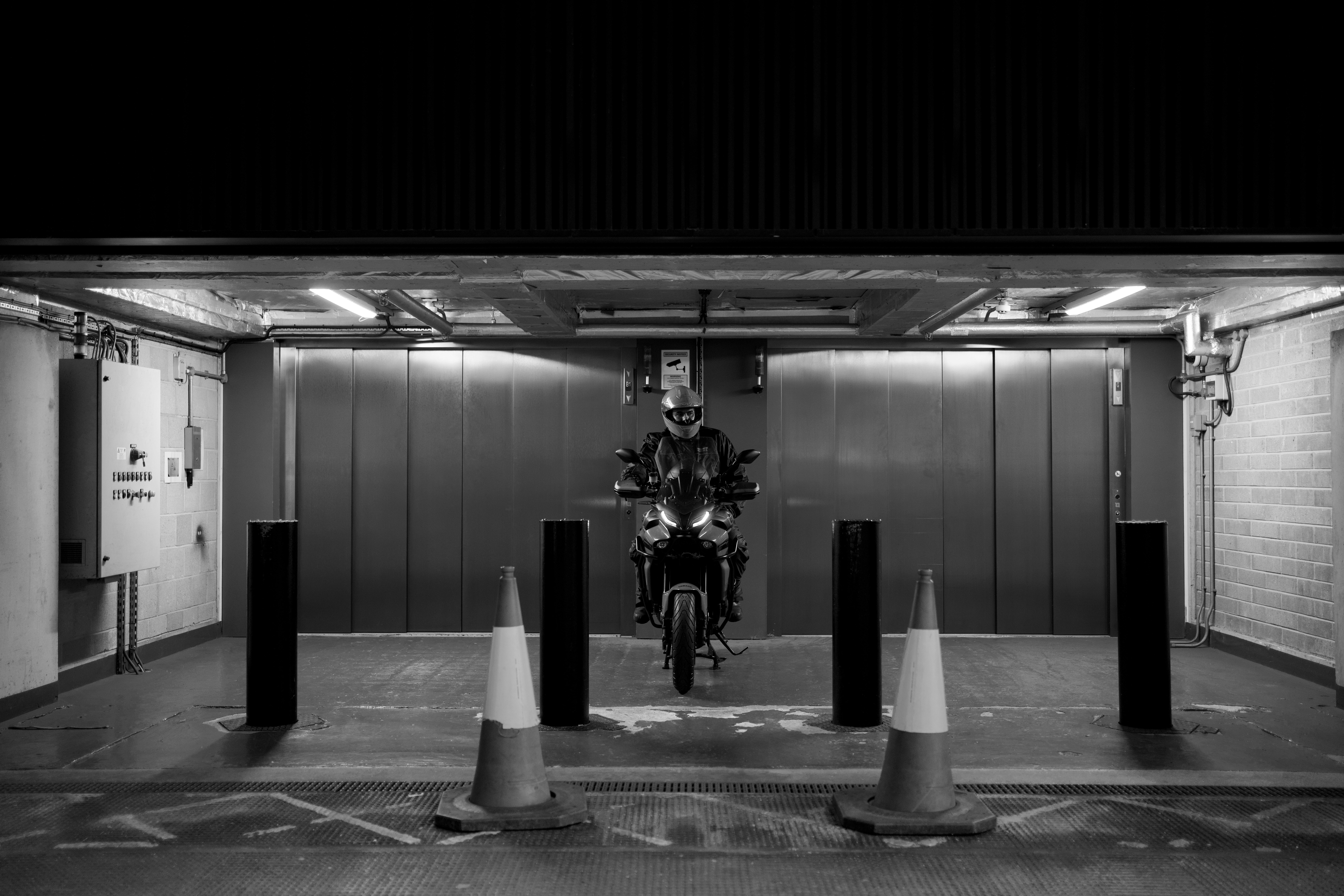 Motorcyclist in a dark garage with traffic cones.