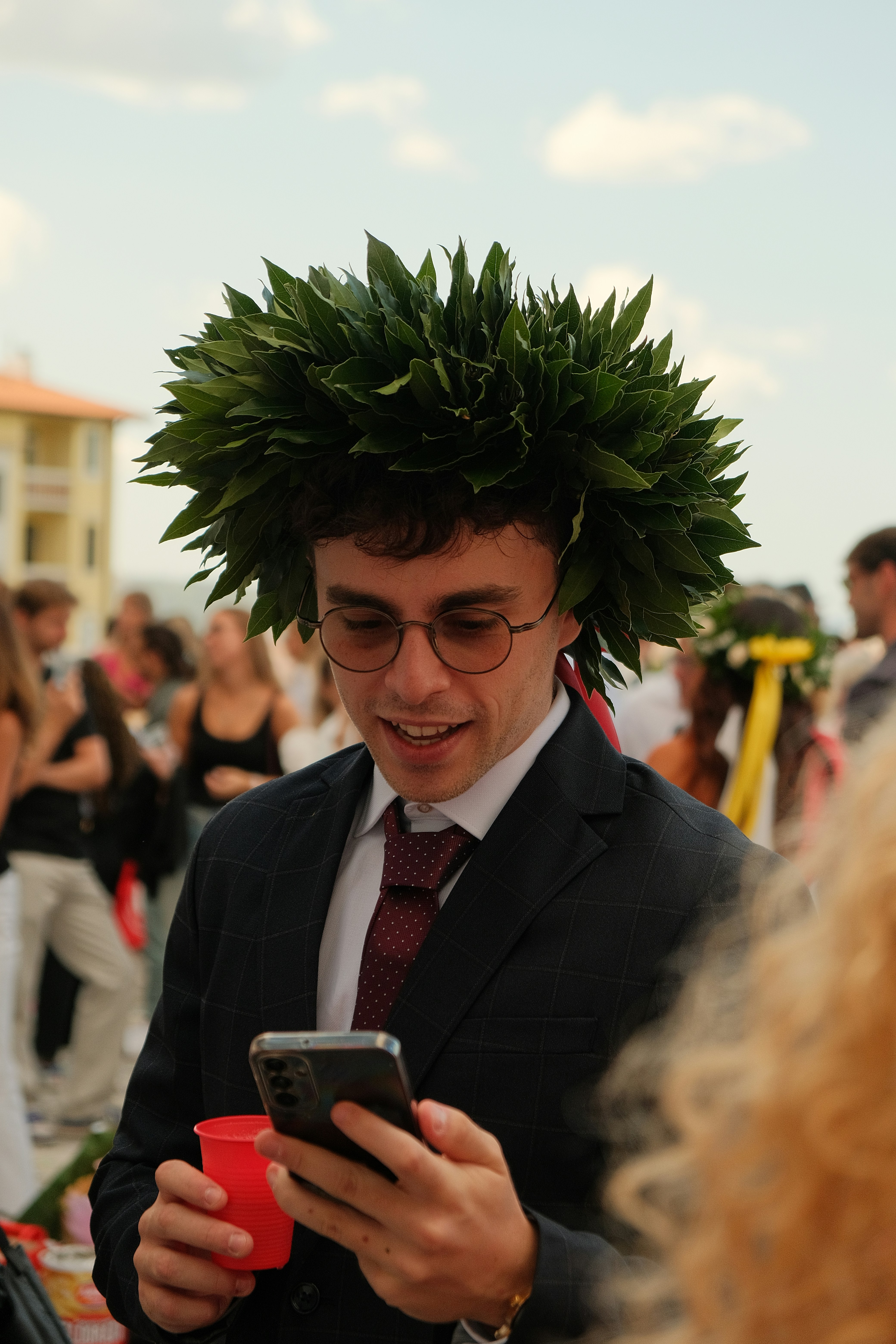 Saying hello to the relatives down south oh his special day | Young man wearing a laurel wreath and suit with phone