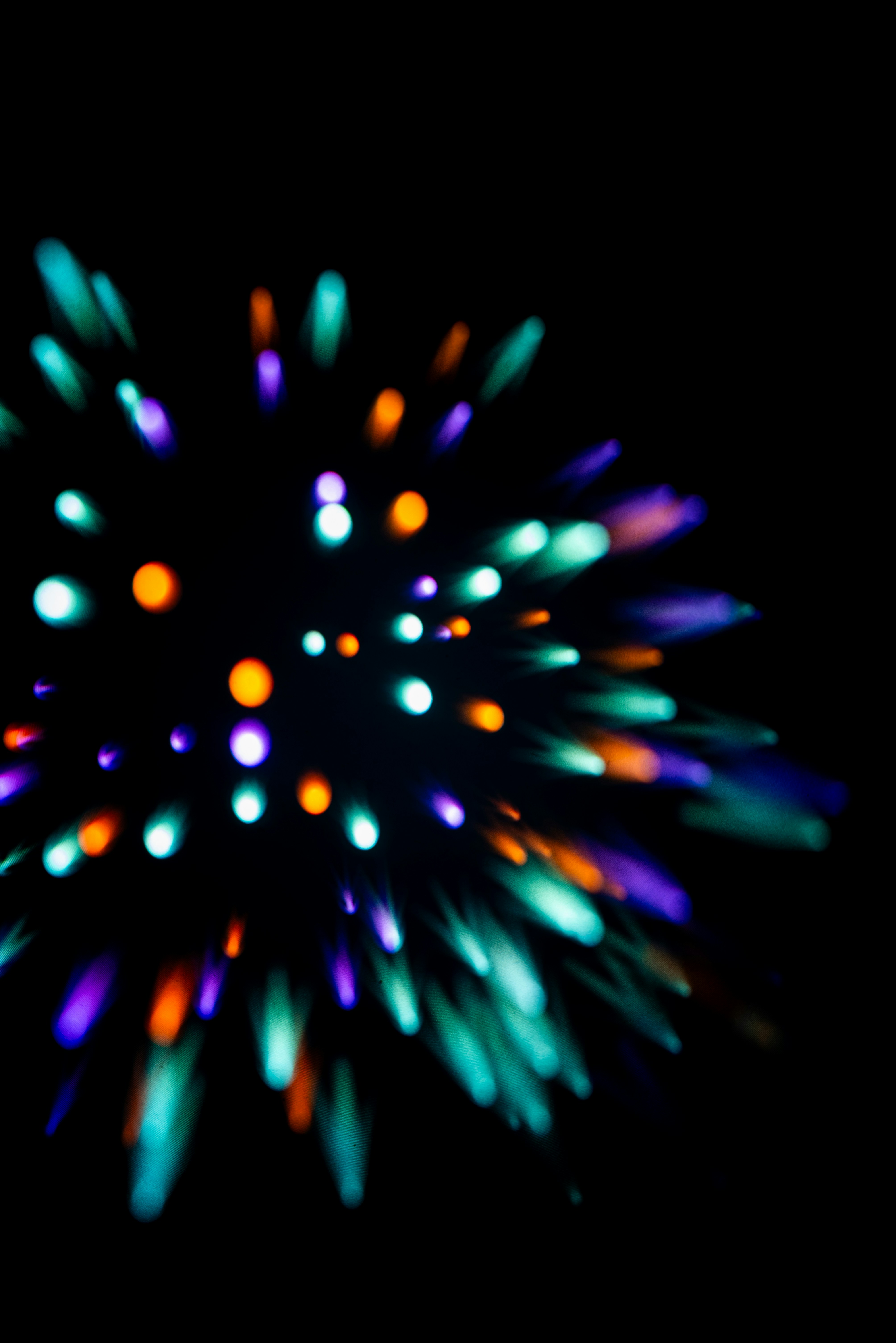 Abstract visual of vibrant light trails radiating from a central point against a dark background. The dynamic interplay of colors creates a mesmerizing effect.