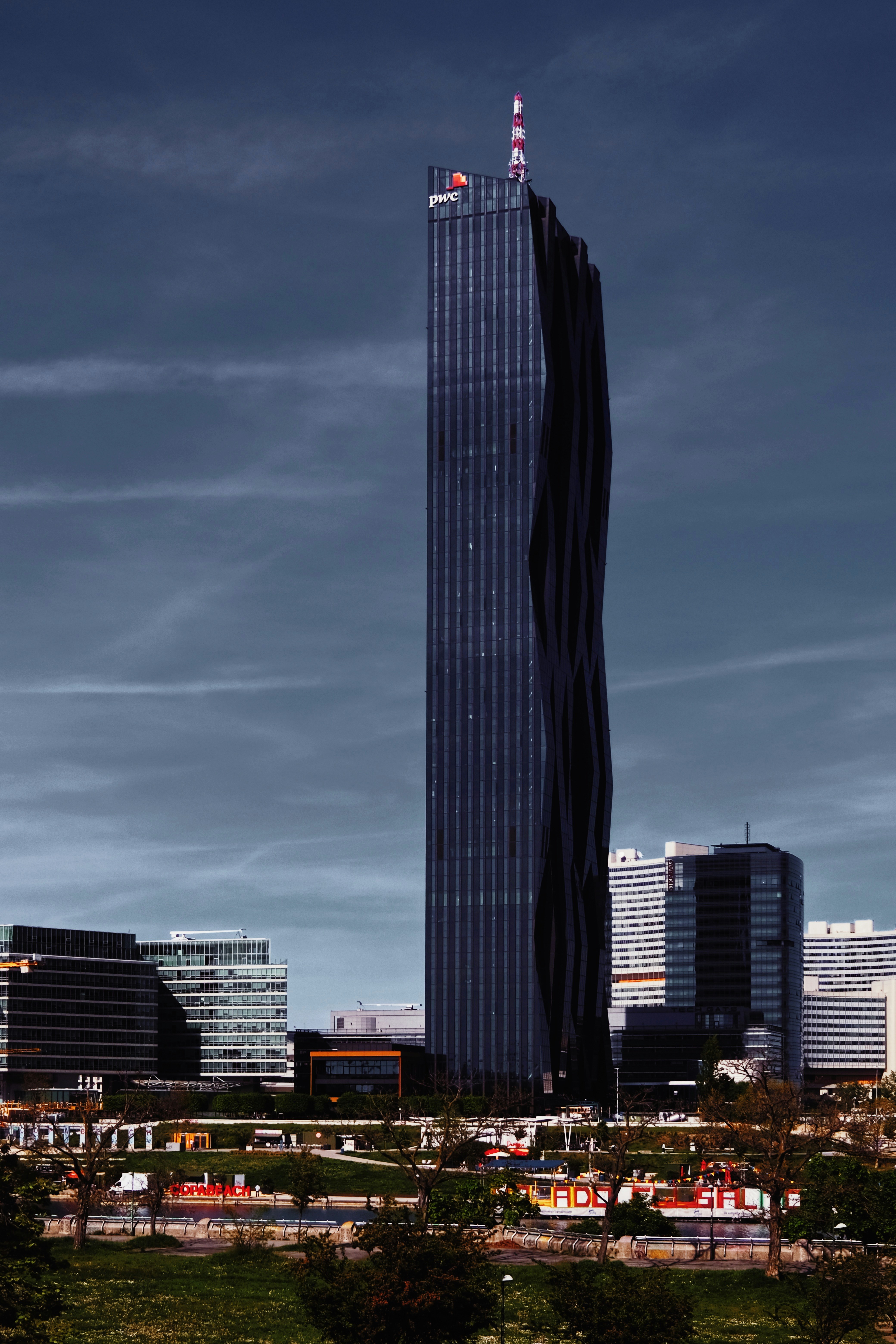 Tall modern skyscraper against a cloudy sky.