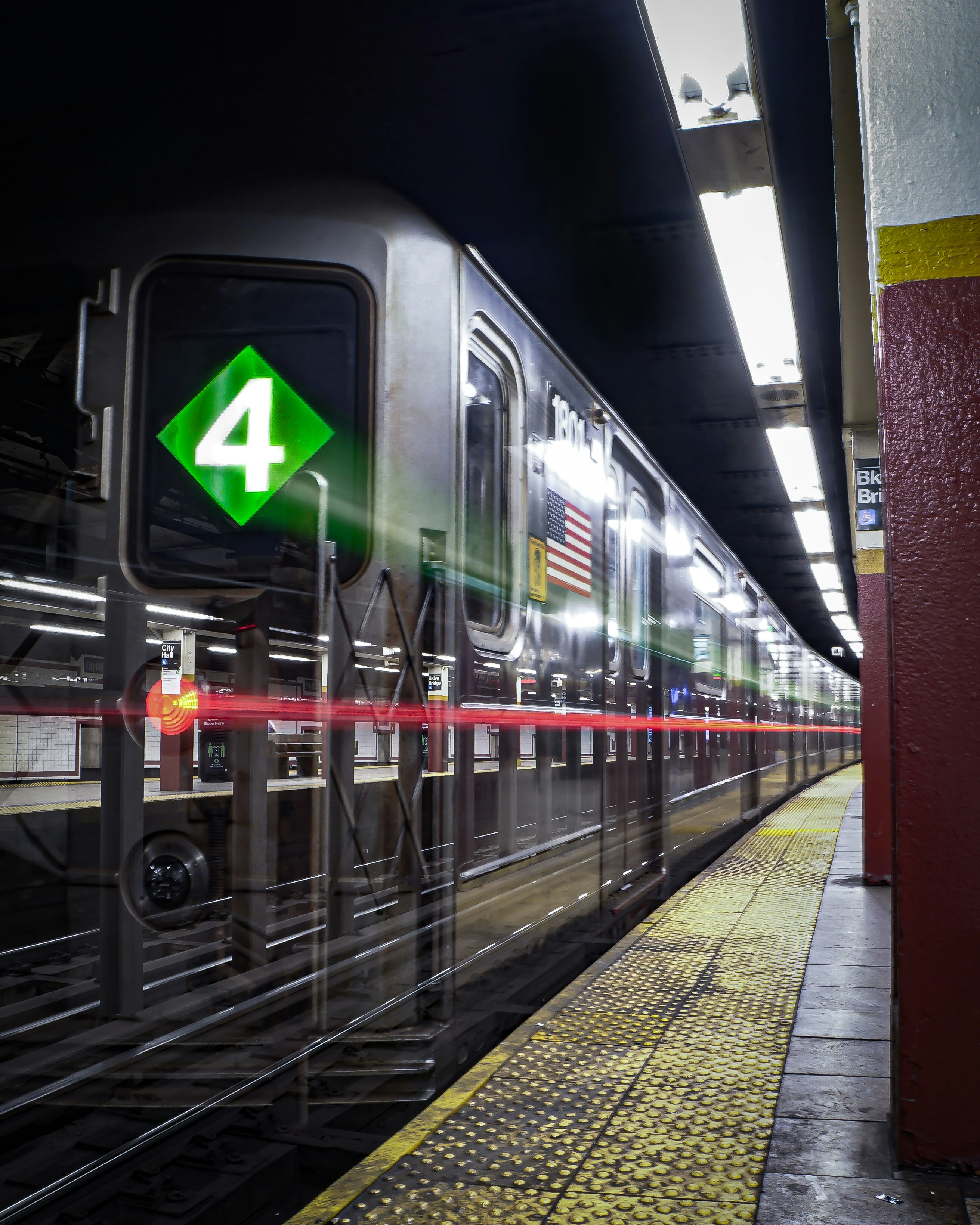 A subway train rushes through a station, showcasing its vibrant green number and motion blur. The platform's yellow tiles add to the urban atmosphere.