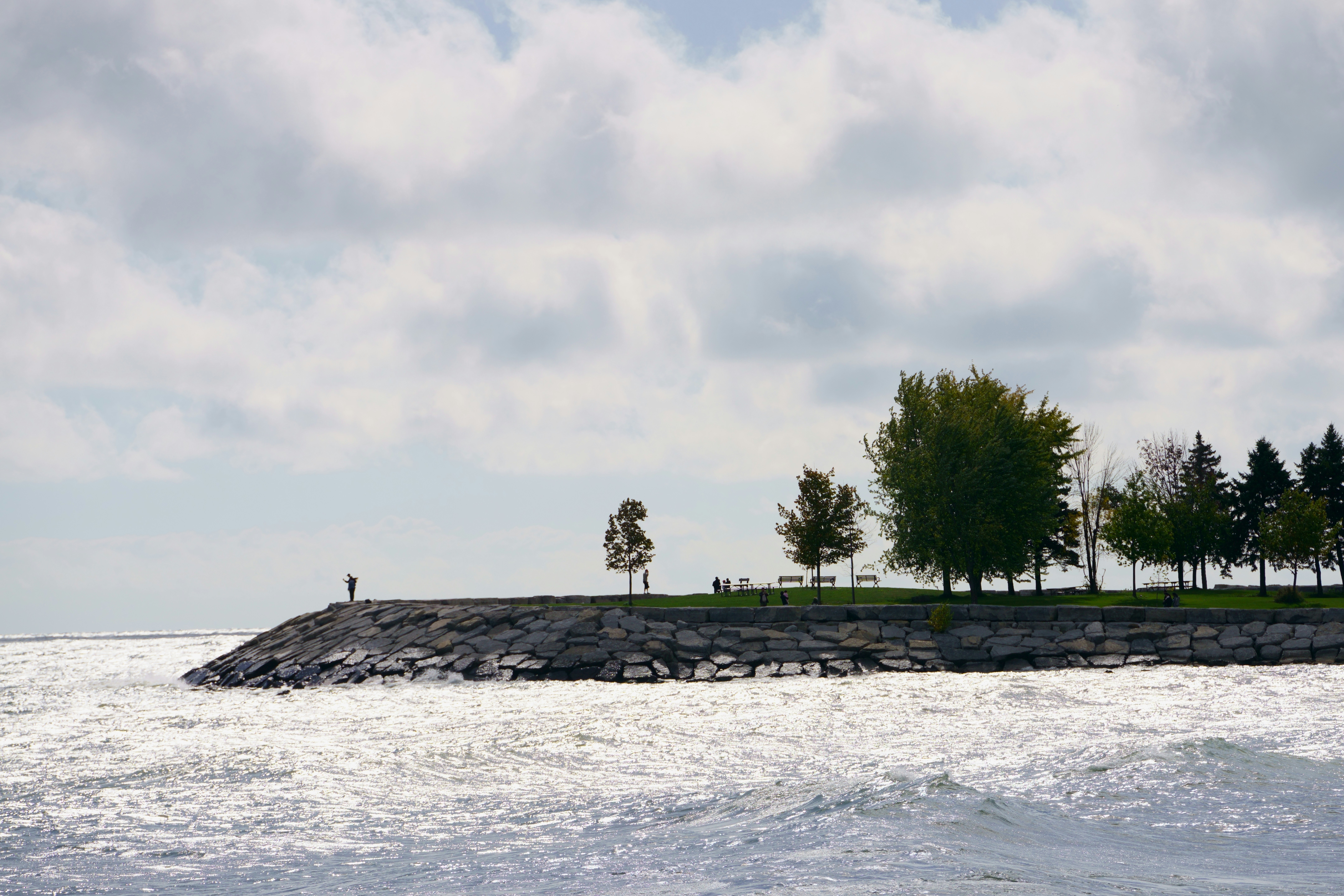 A person stands on a rocky shore overlooking water