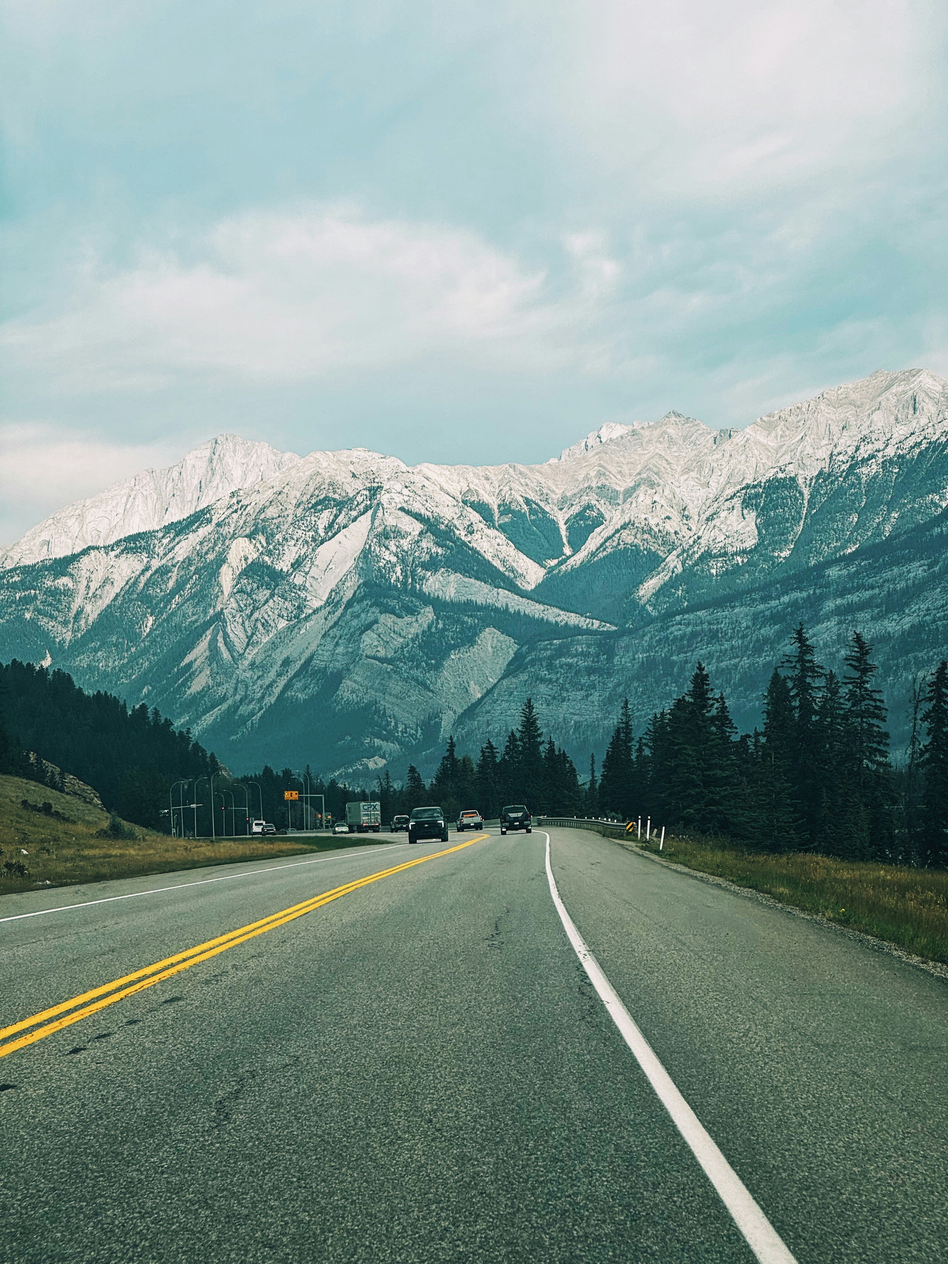 Cars driving on a road towards snowy mountains.