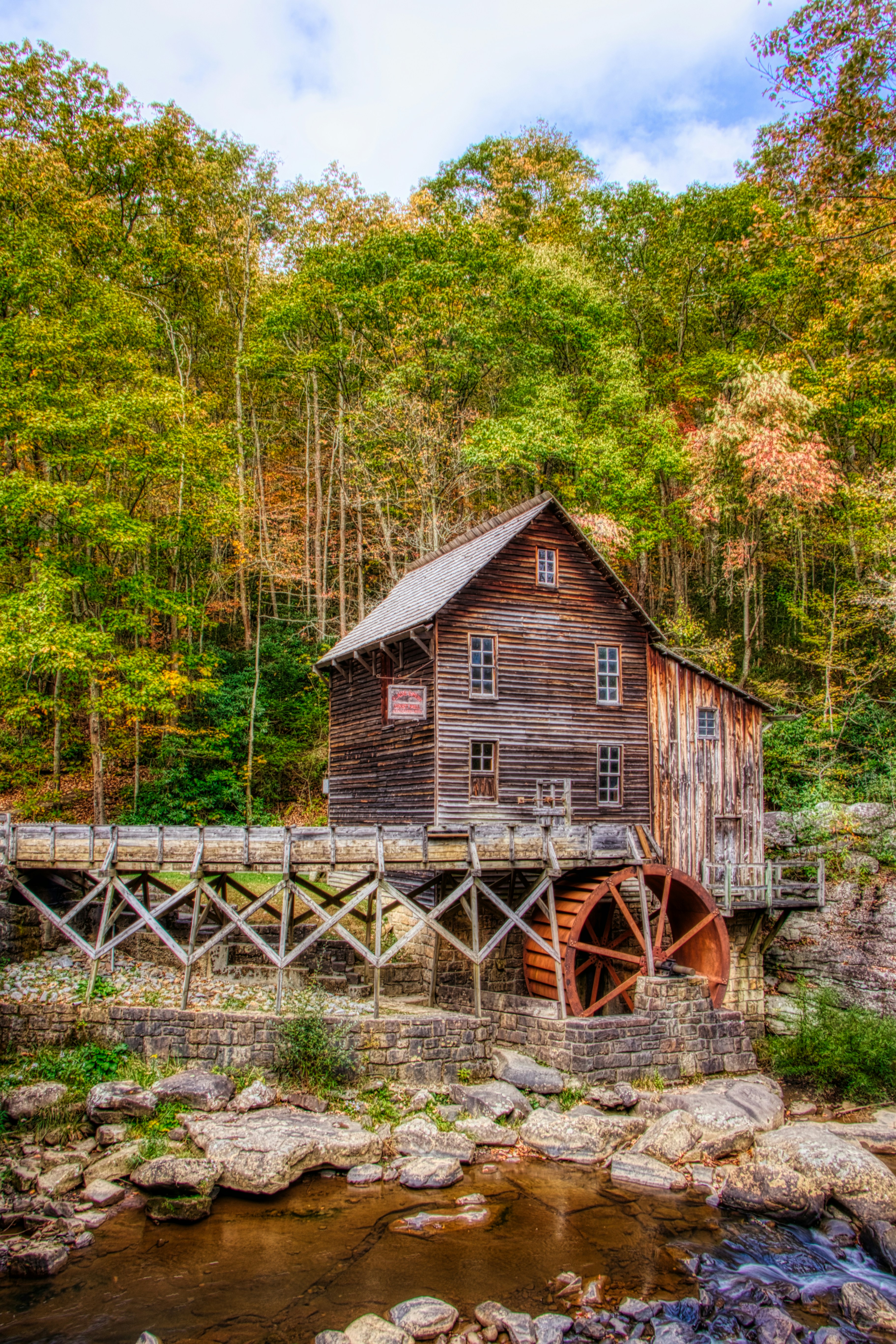 Old wooden mill with water wheel by rocky stream