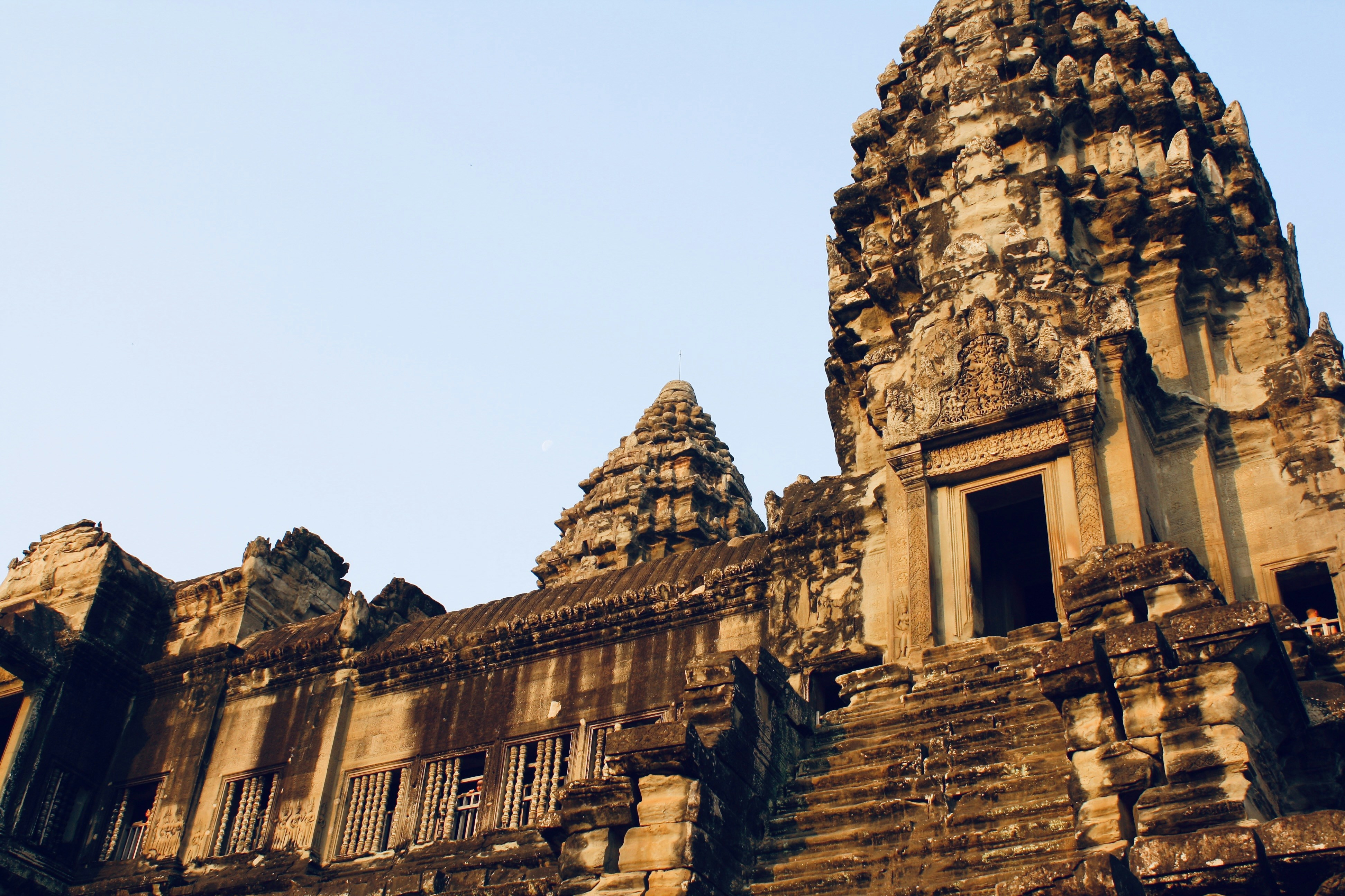 朝日に照らされているカンボジアアンコールワットの第三回廊 | Ancient stone temple ruins against a clear sky