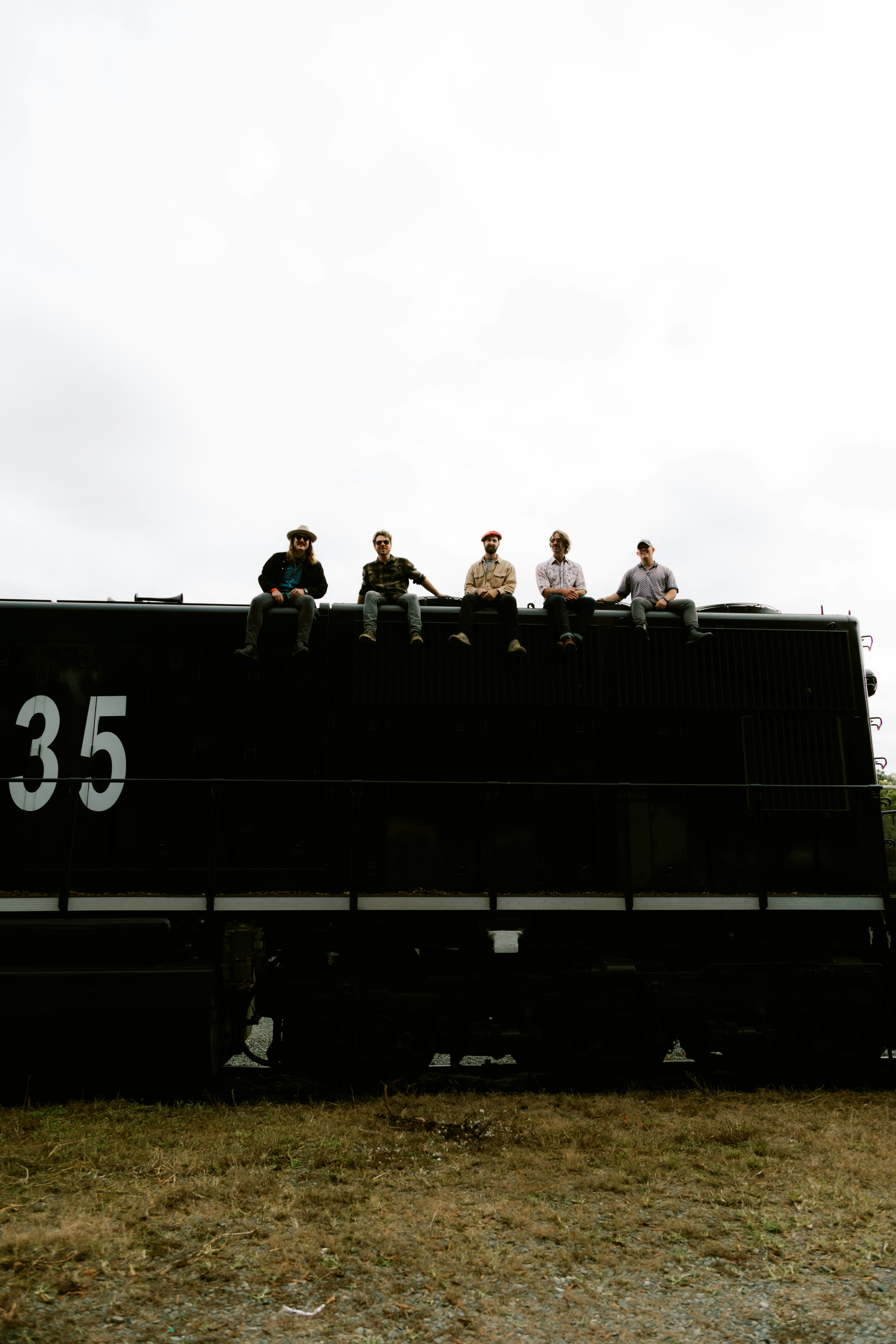 Five men sit atop a black train car.