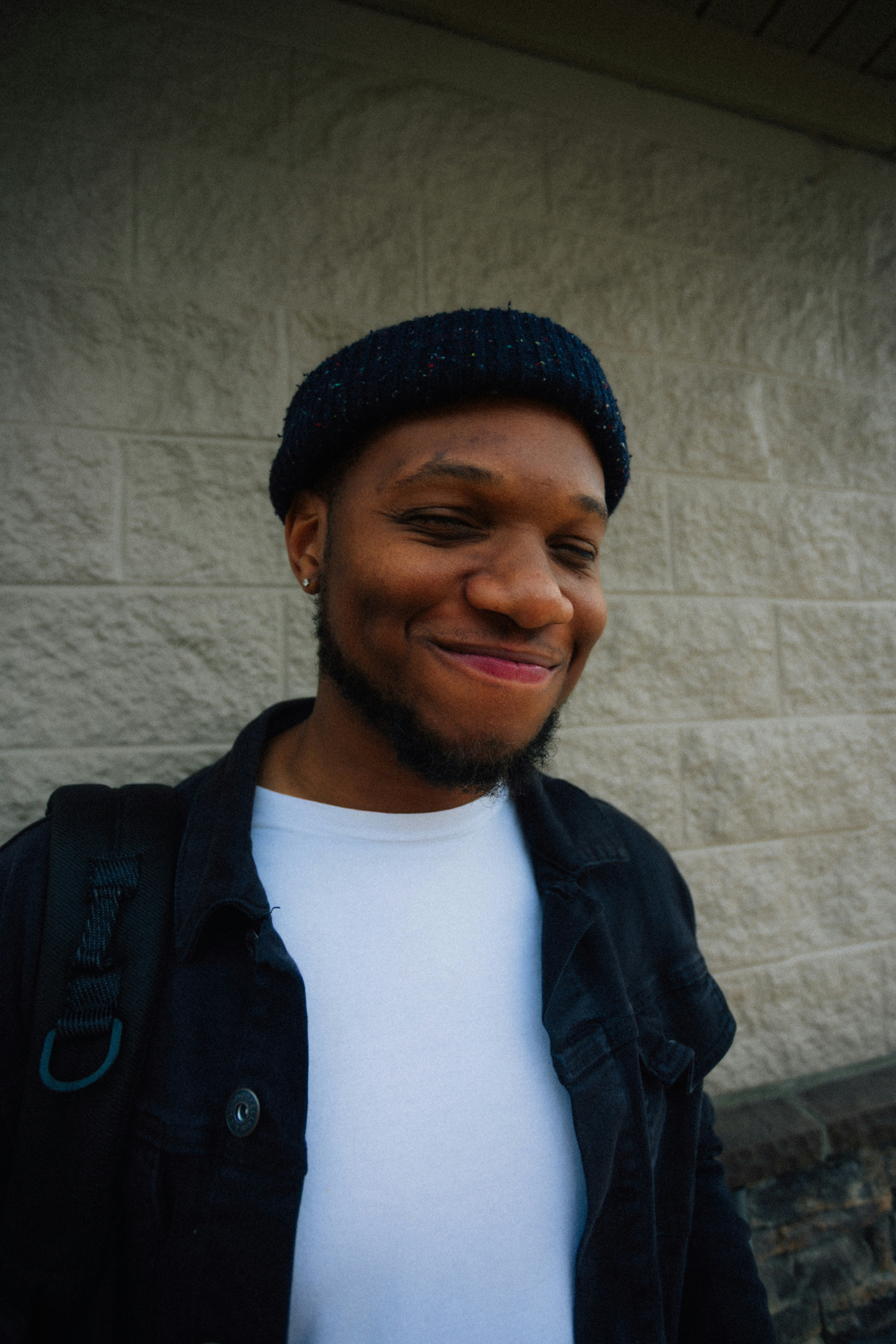 A smiling man wearing a beanie and jacket.