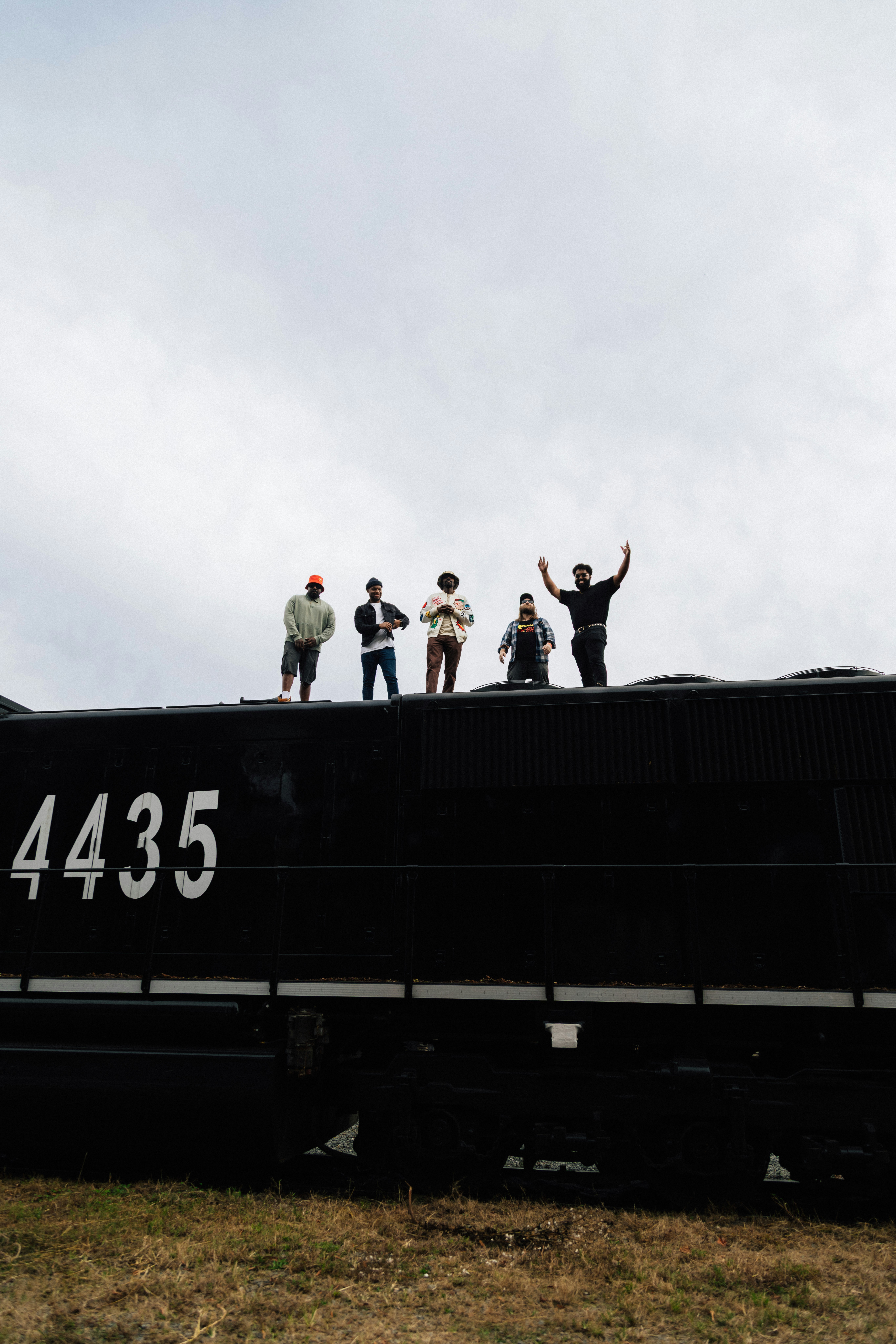 Five people stand on top of a train car