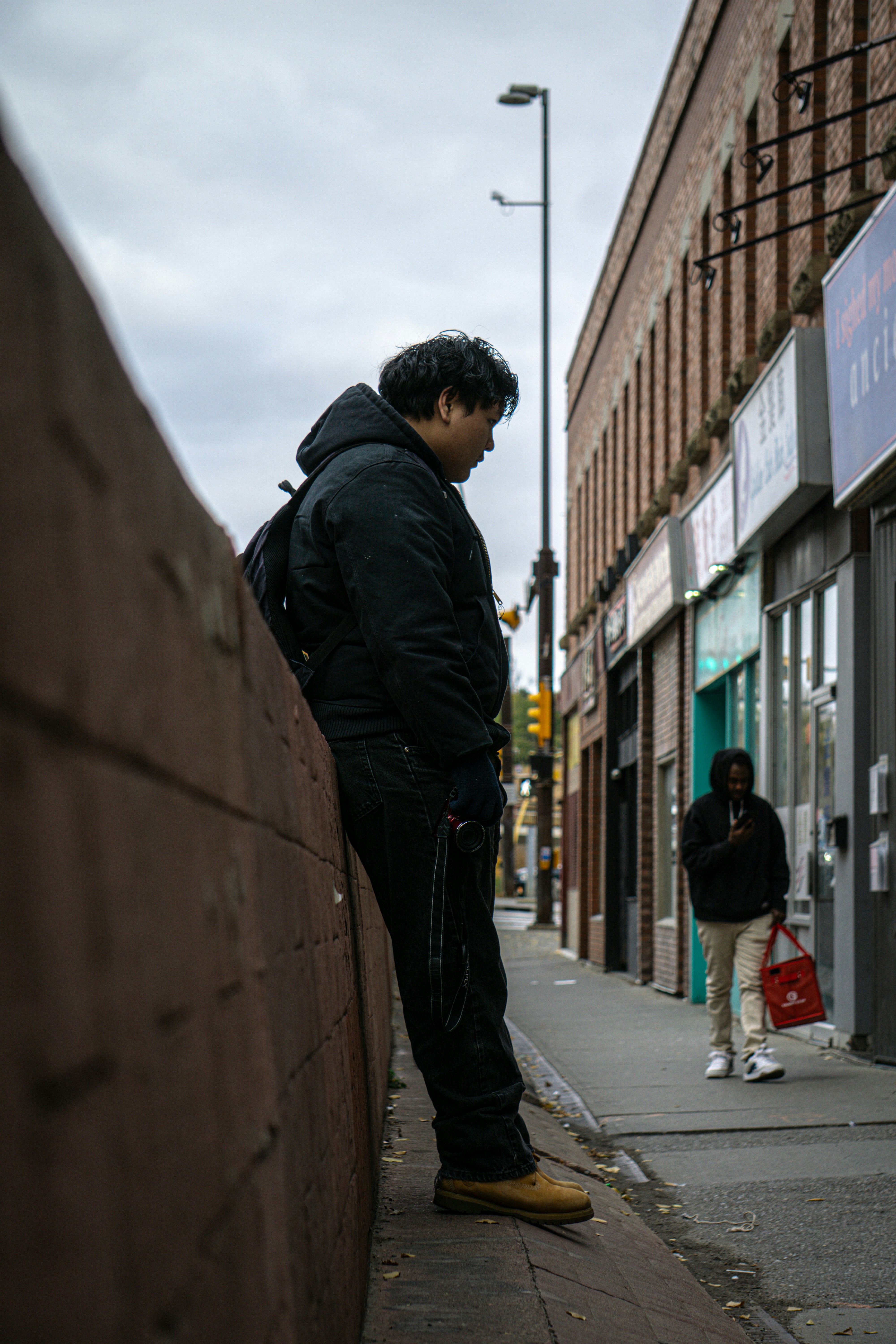 Man leaning against a wall on a city street.
