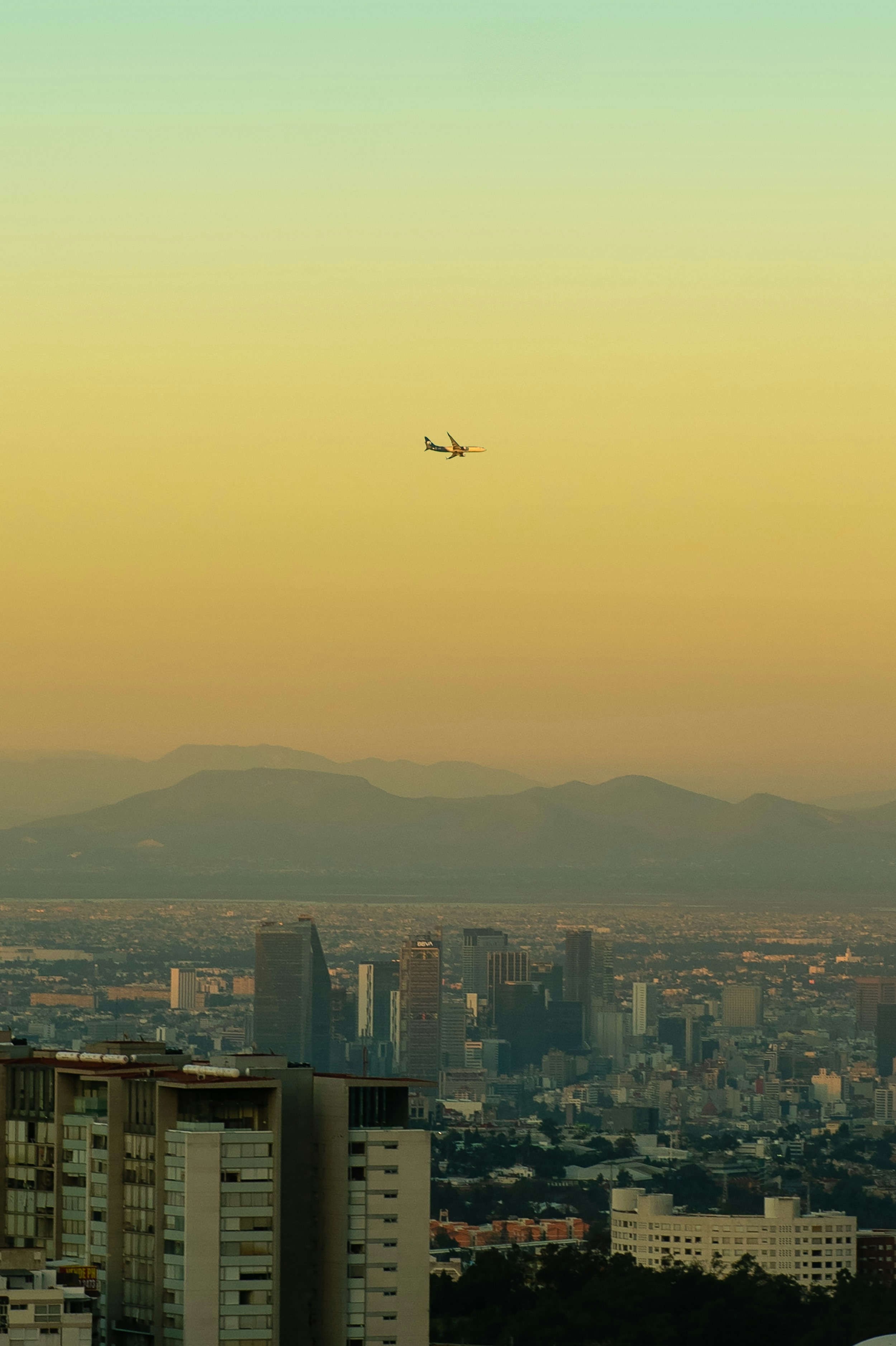 Airplane flying over city skyline at sunset