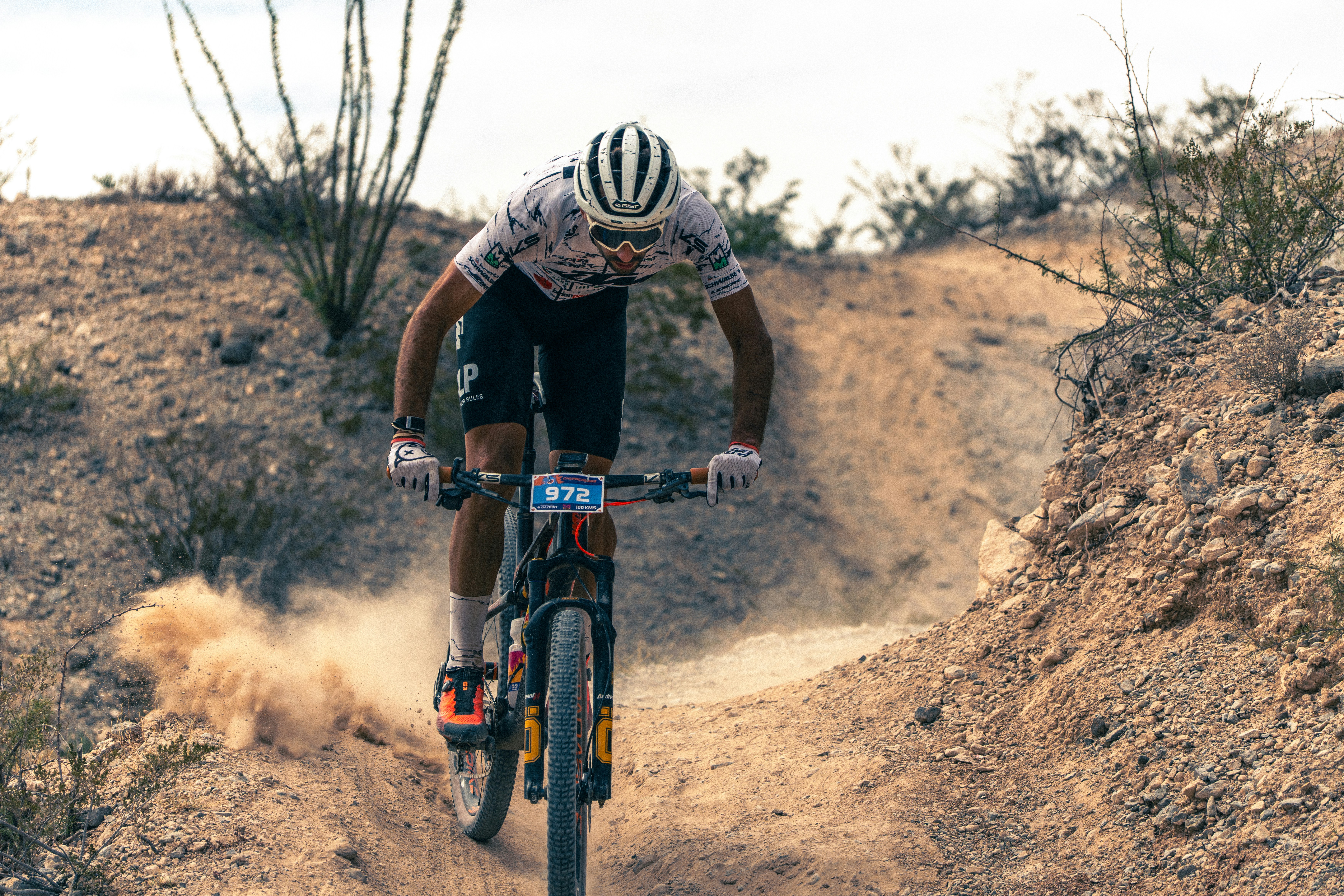 Mountain biker riding down a dusty desert trail.