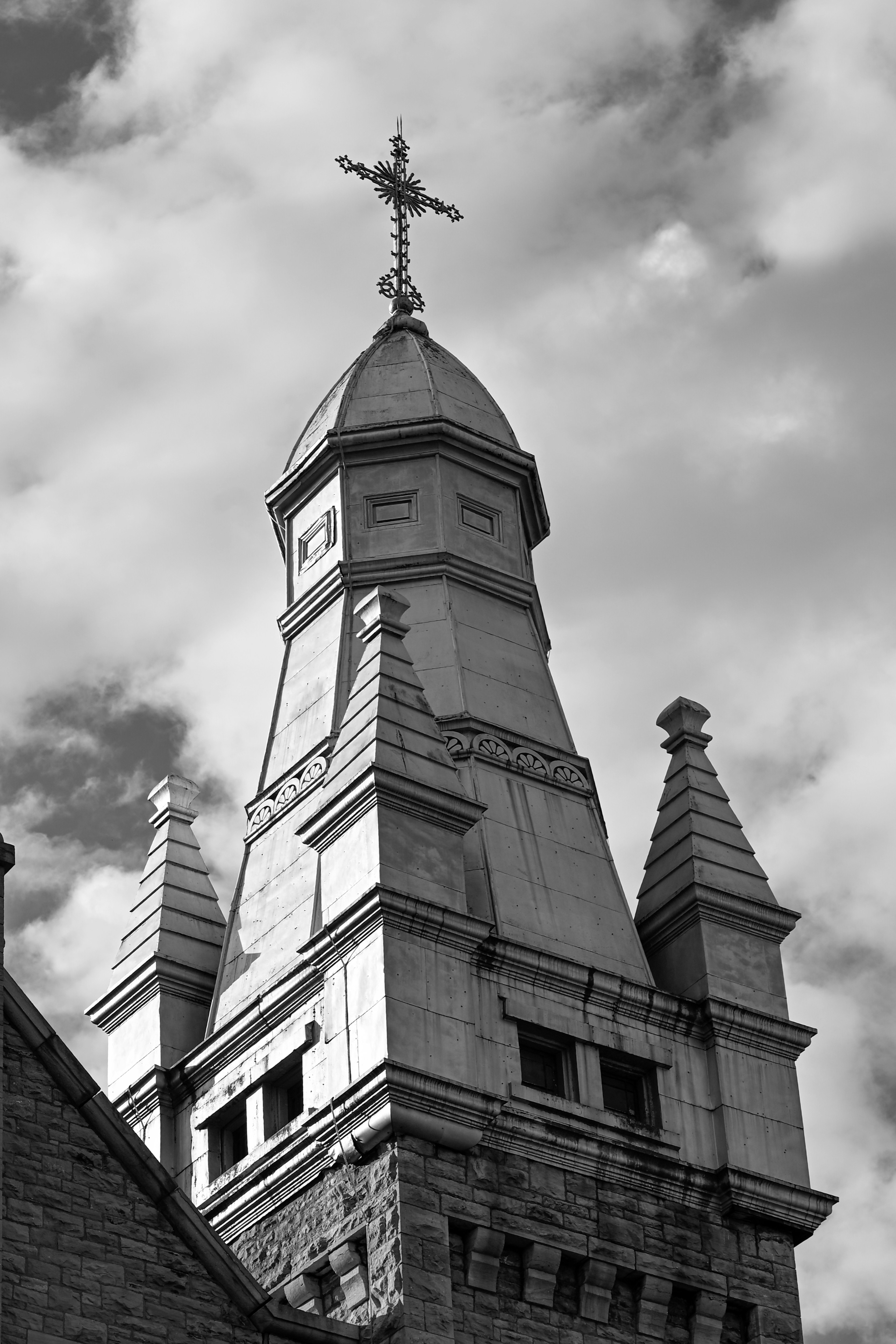 Church steeple with cross against cloudy sky