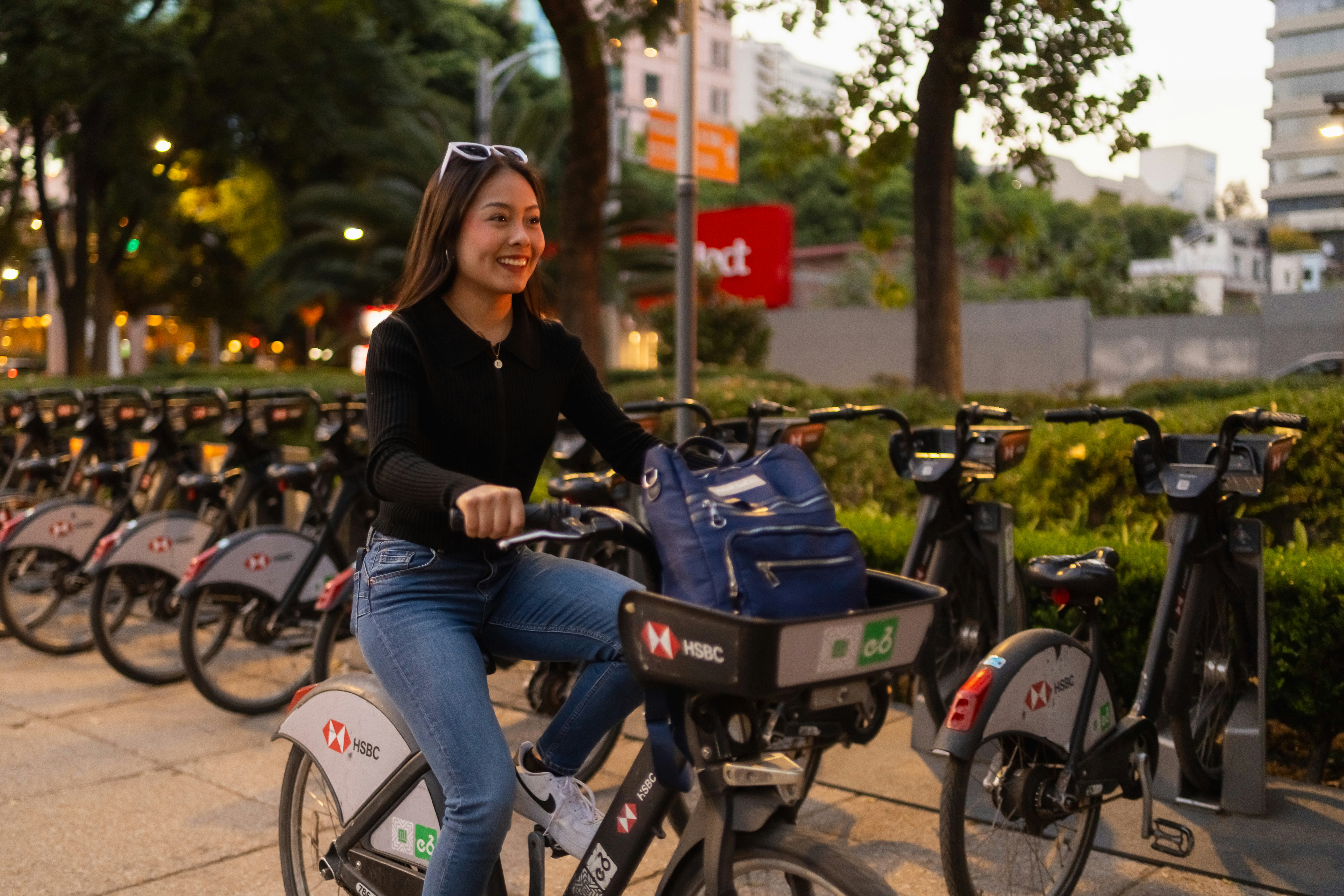 A woman smiles while riding a shared bicycle
