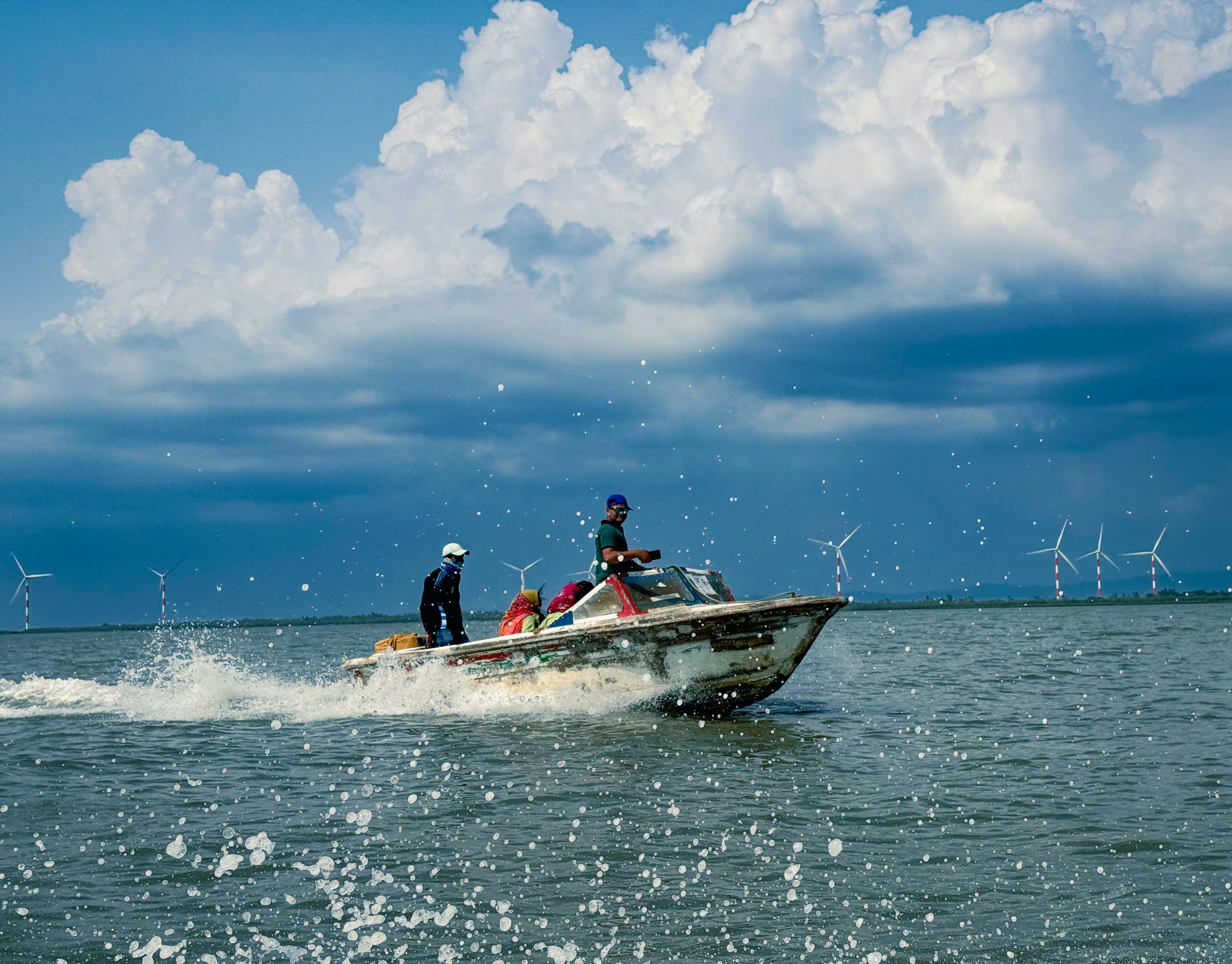 Boat with people sailing past wind turbines