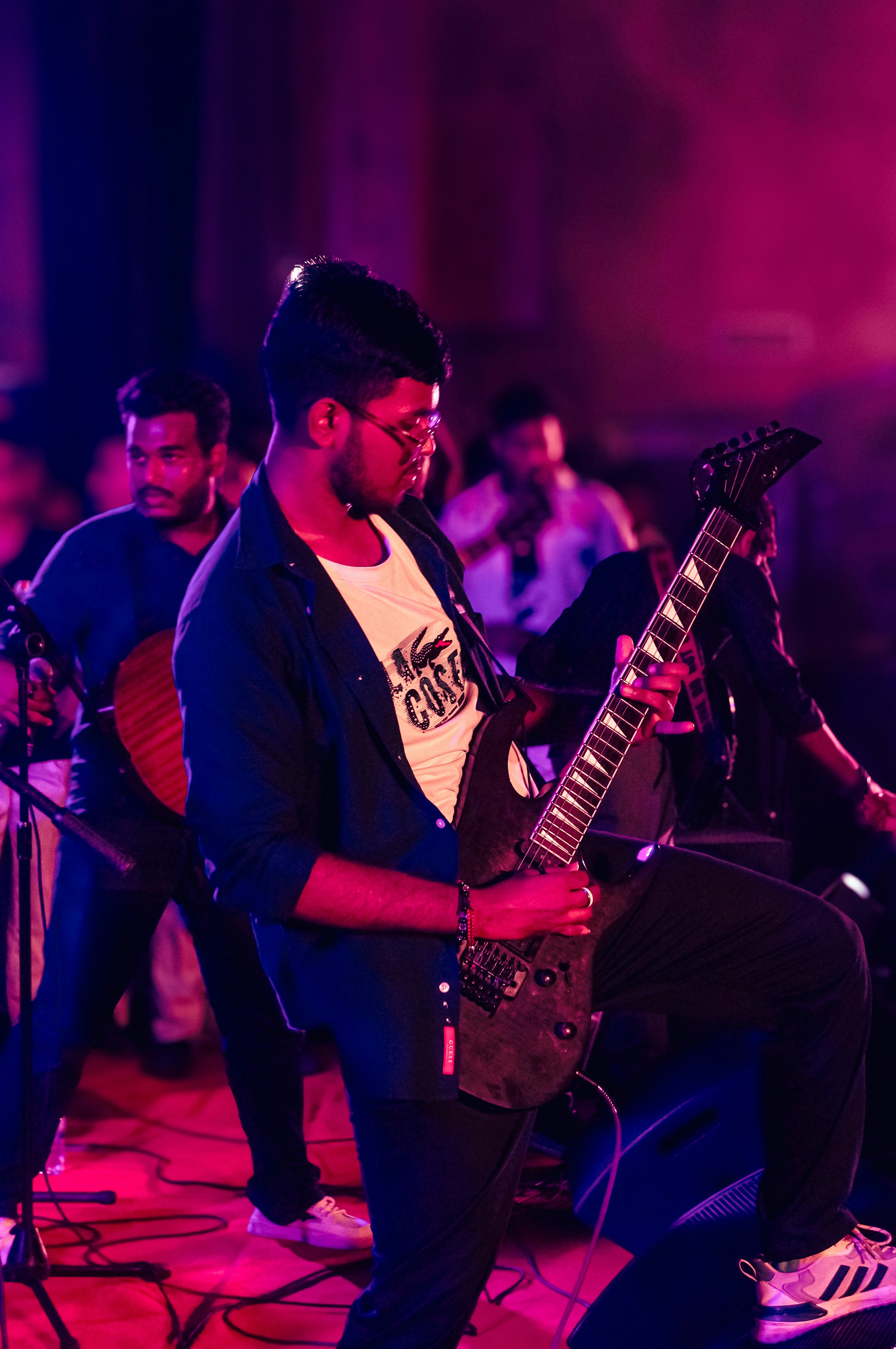 Musician playing electric guitar on stage with band