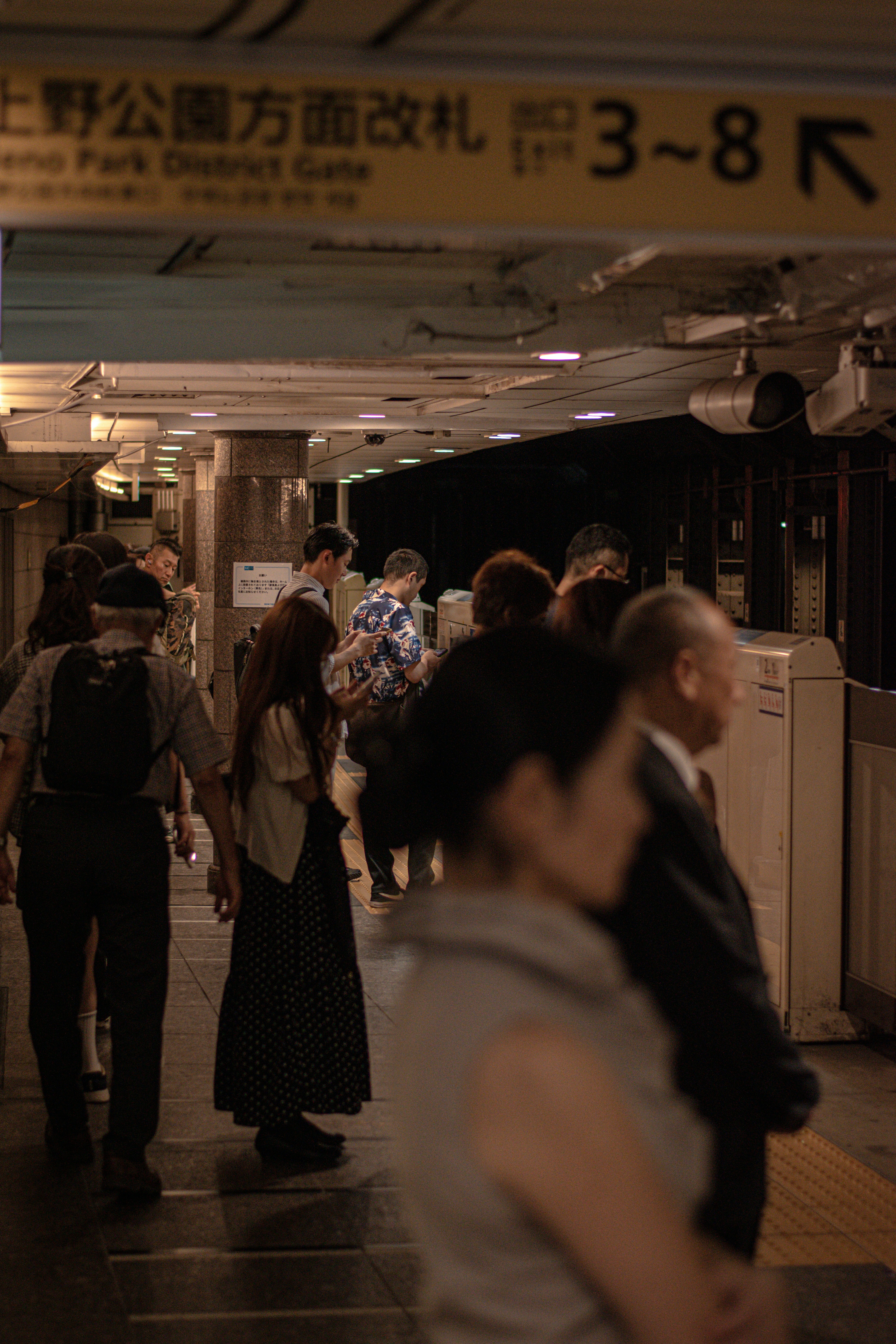 People walking on a subway platform at night.