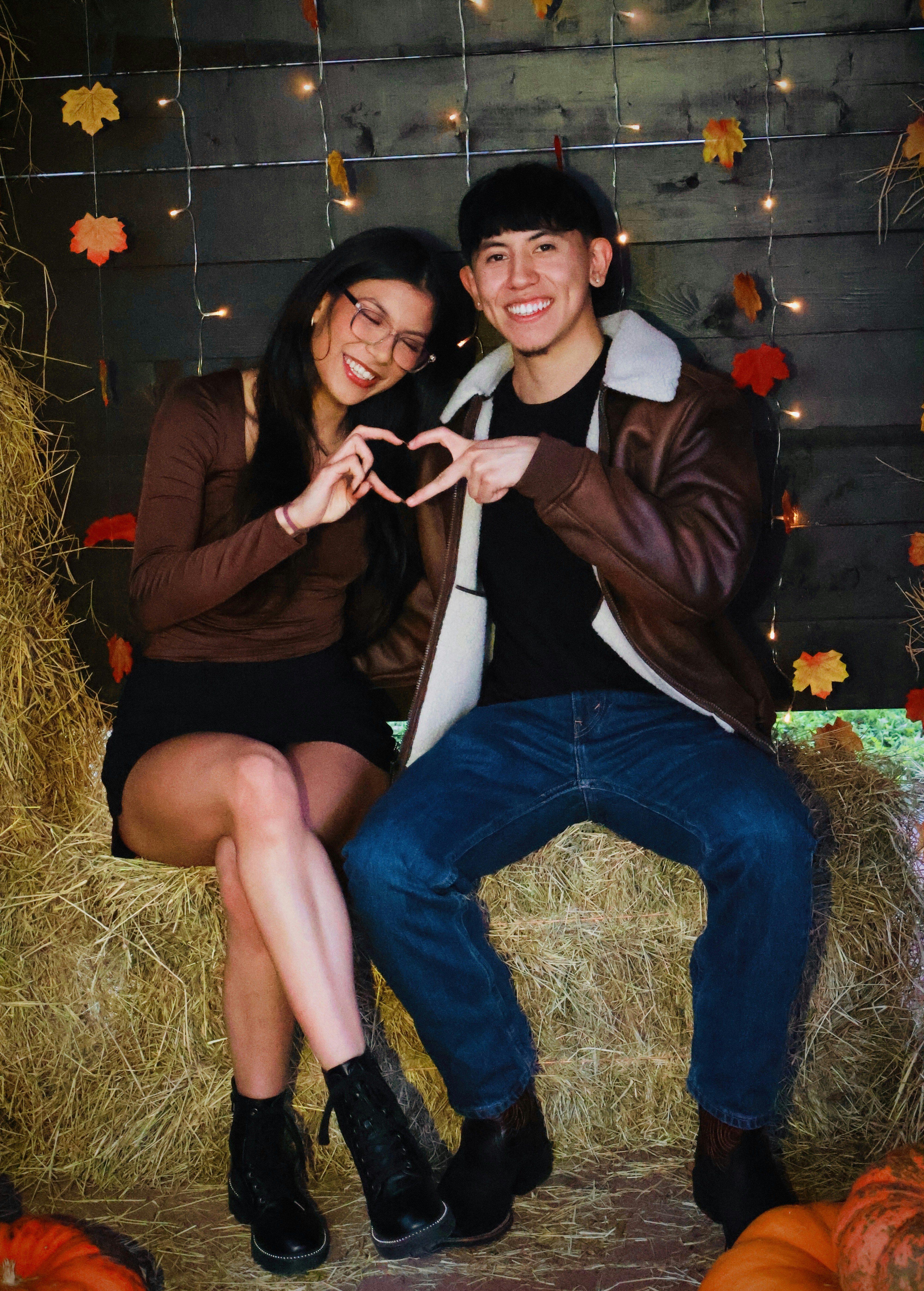 Couple making heart shape with hands on hay bales