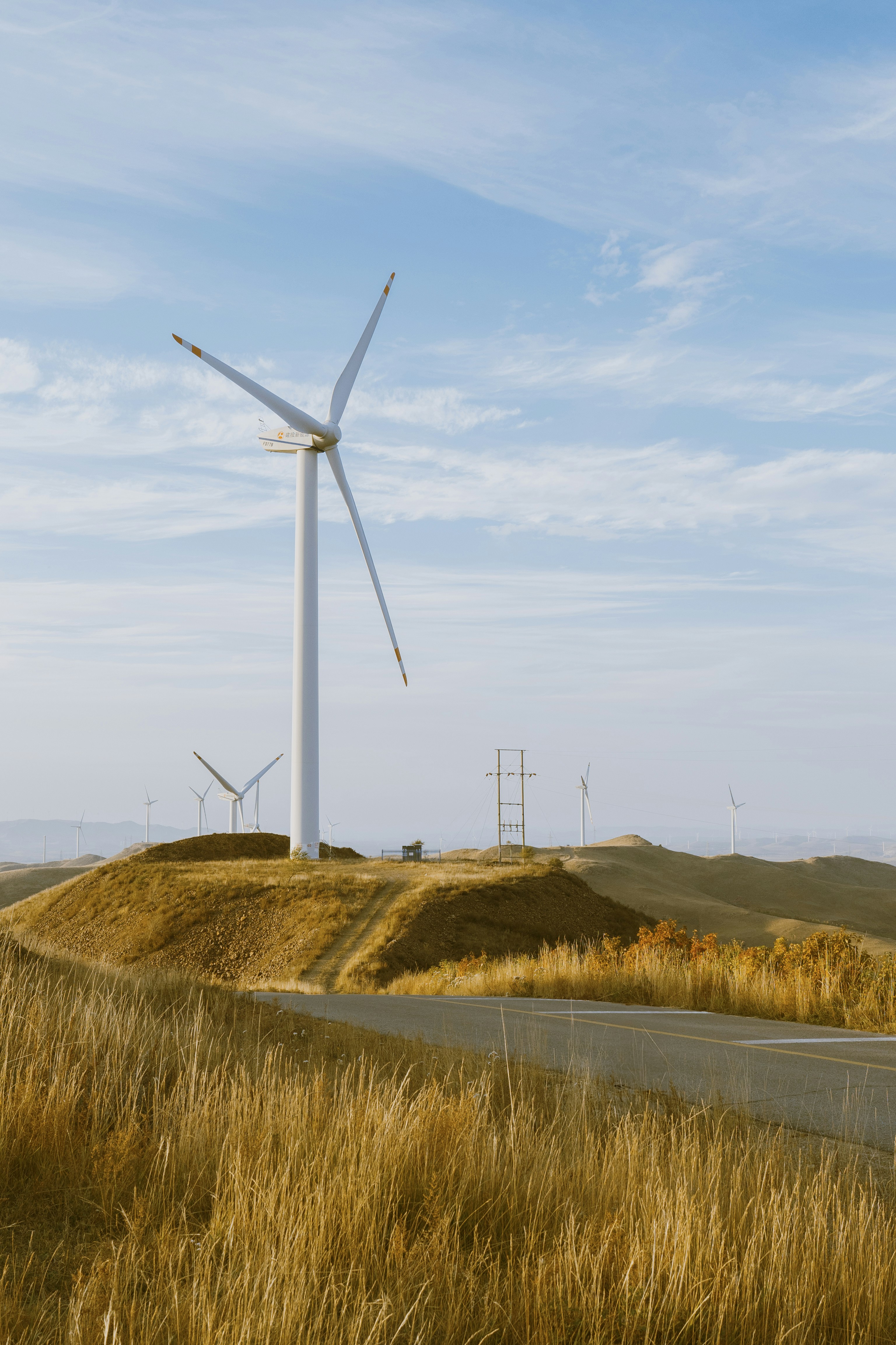 Wind turbines on a grassy hill under a blue sky. photo – Free ...