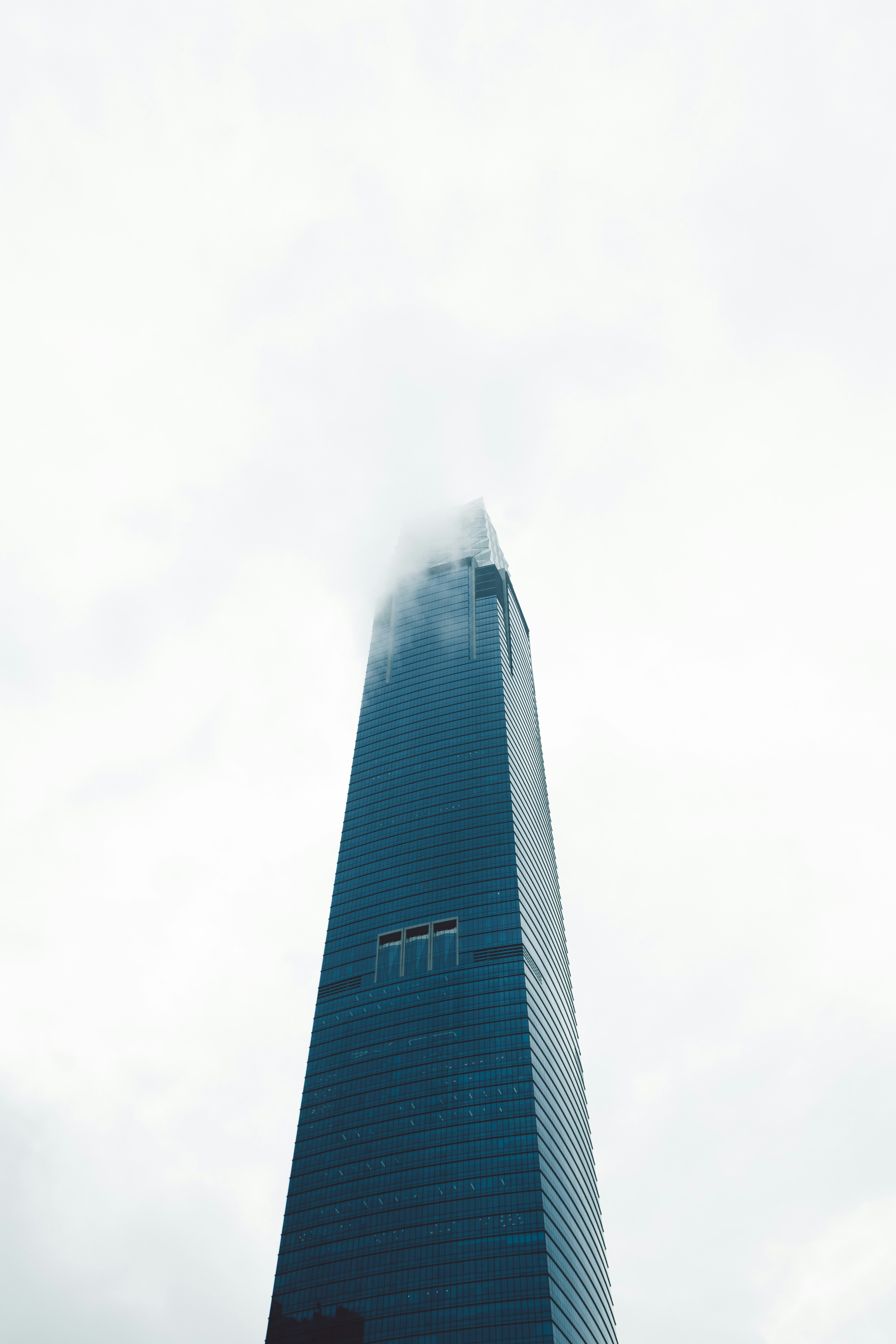 Tall skyscraper disappearing into white clouds