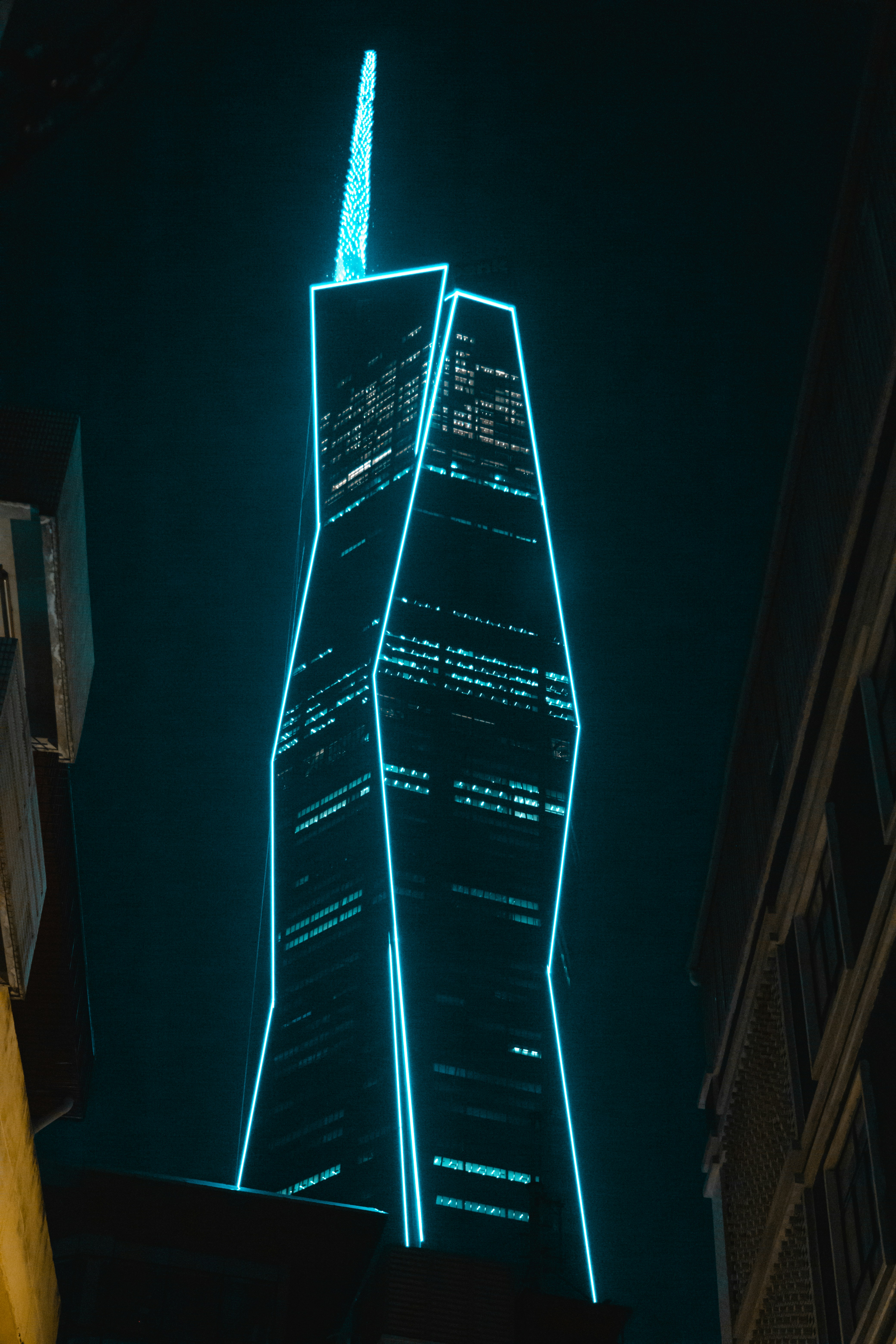 Modern skyscraper illuminated with blue neon lights at night.