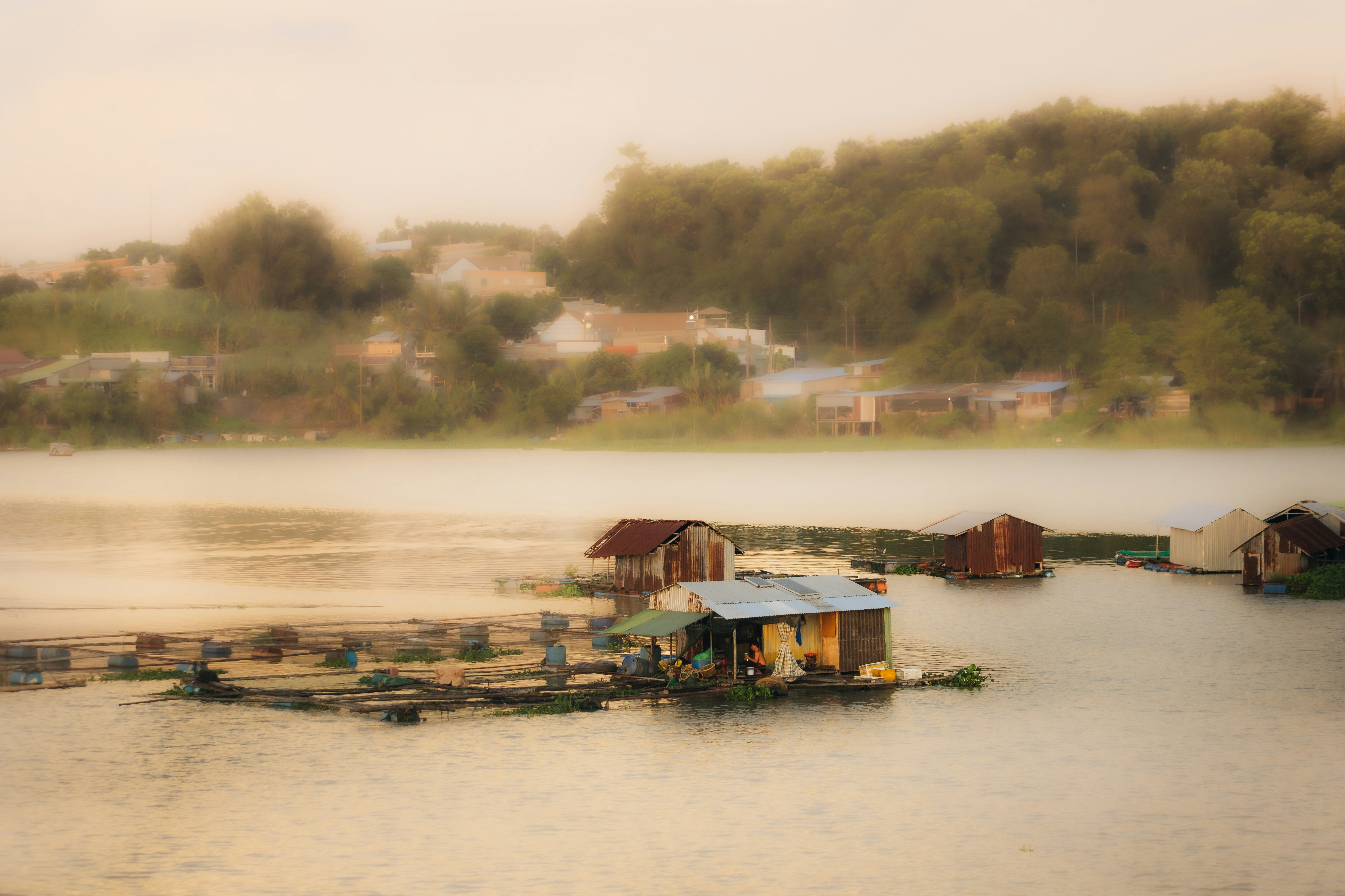 Floating houses on a misty lake with hills