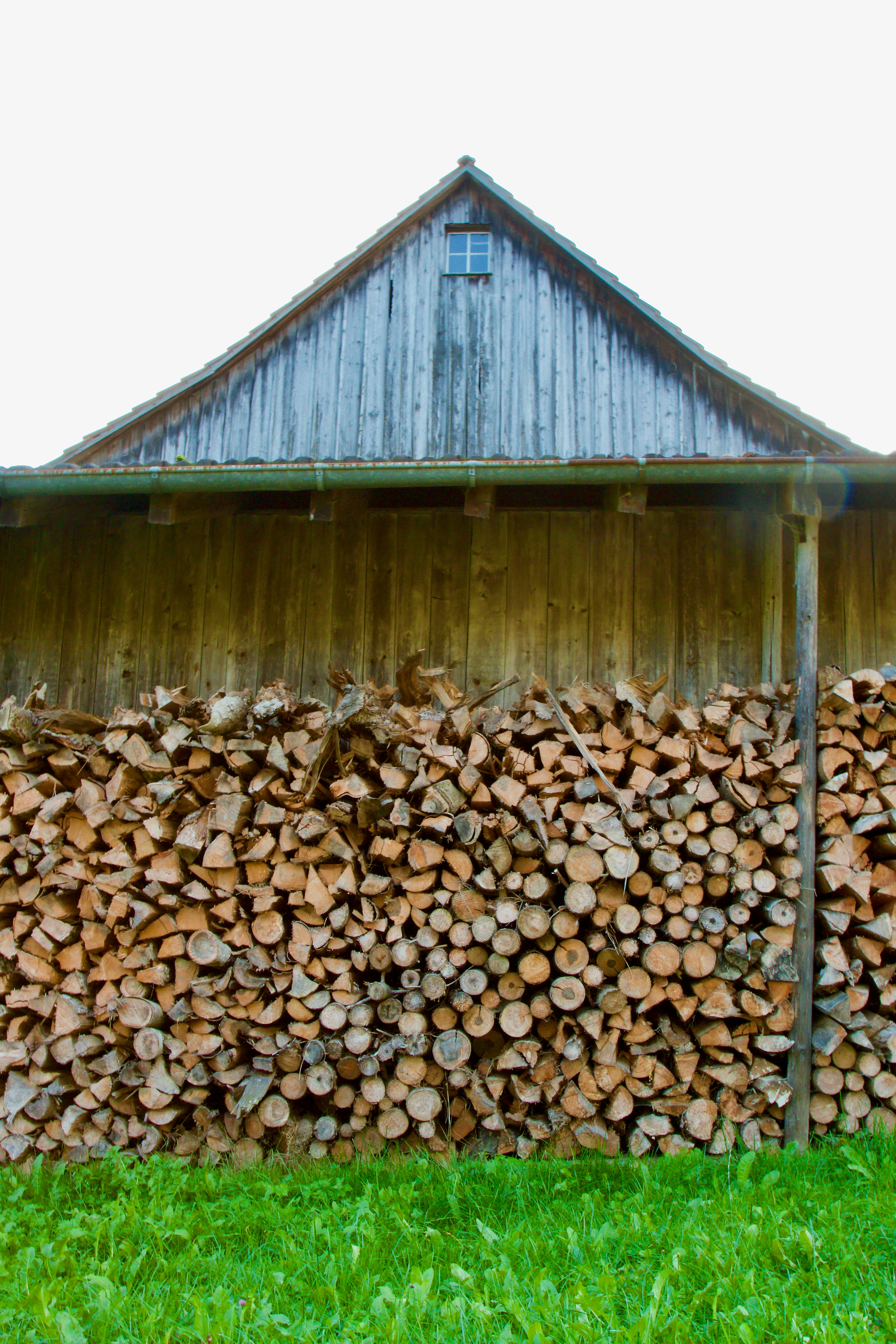 Stacked firewood against a wooden barn wall.