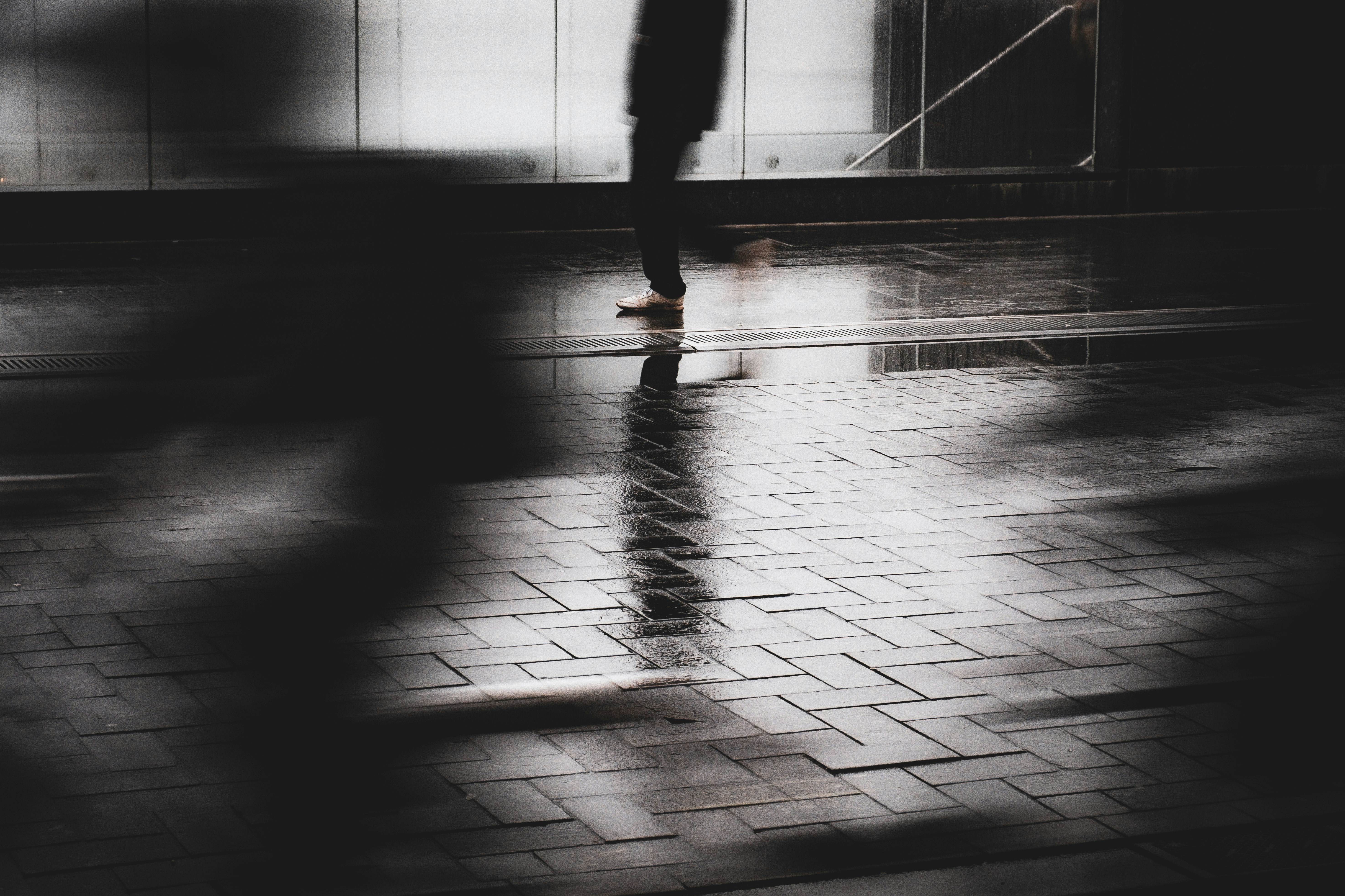 A person stands on a wet tiled surface.