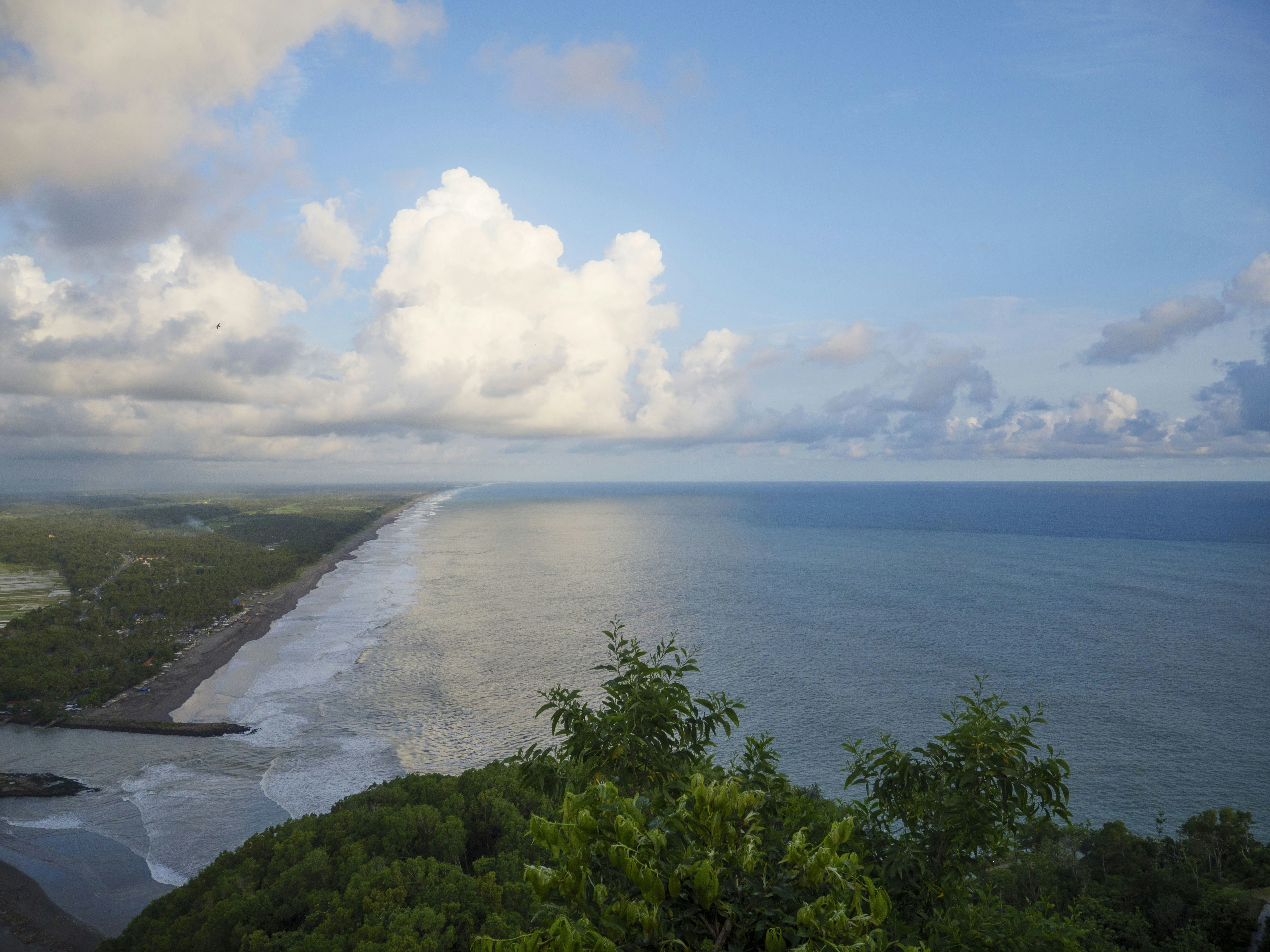 Long sandy beach meets the blue ocean under clouds.