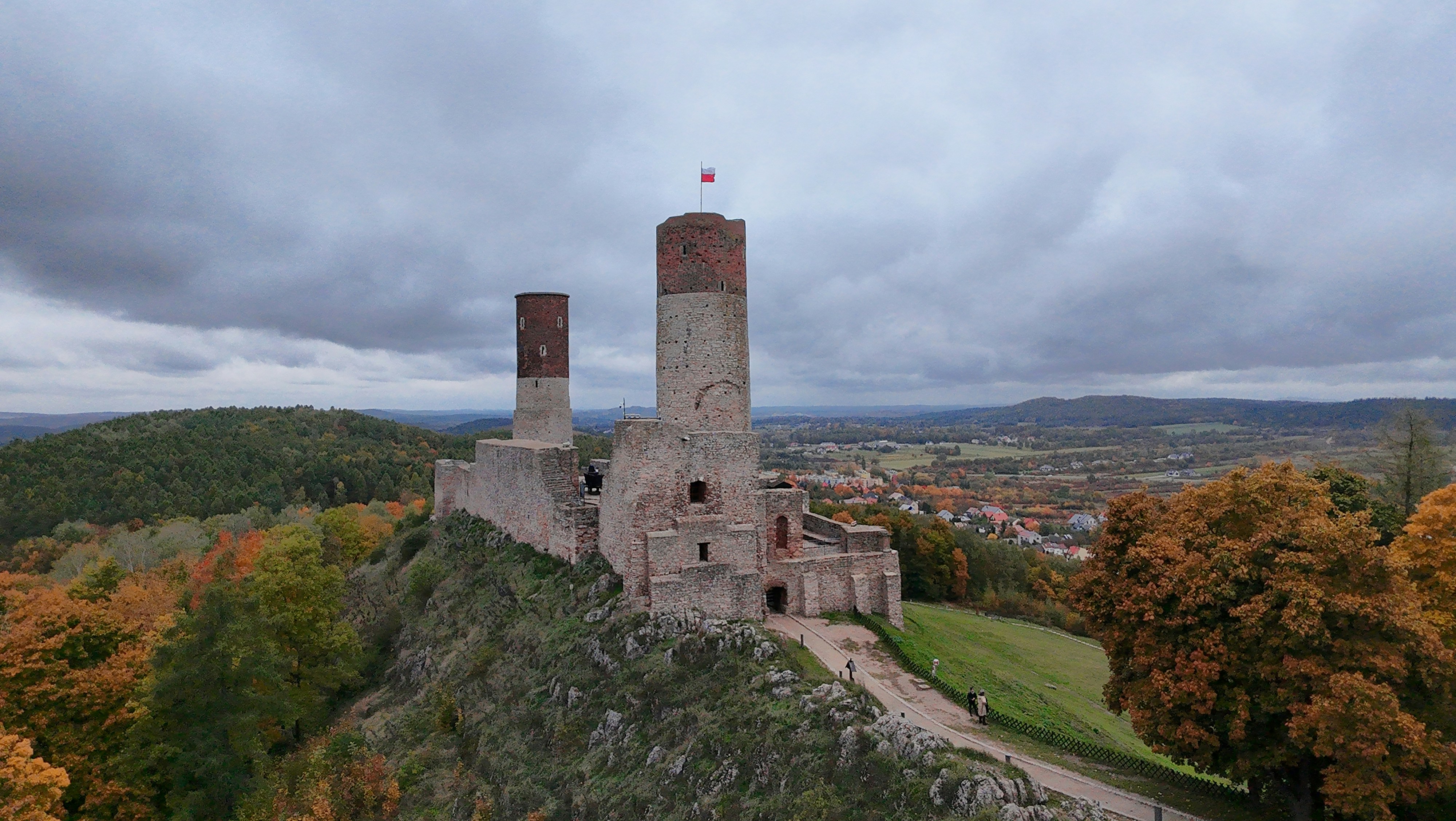 Ruined castle towers on a hill with autumn trees.